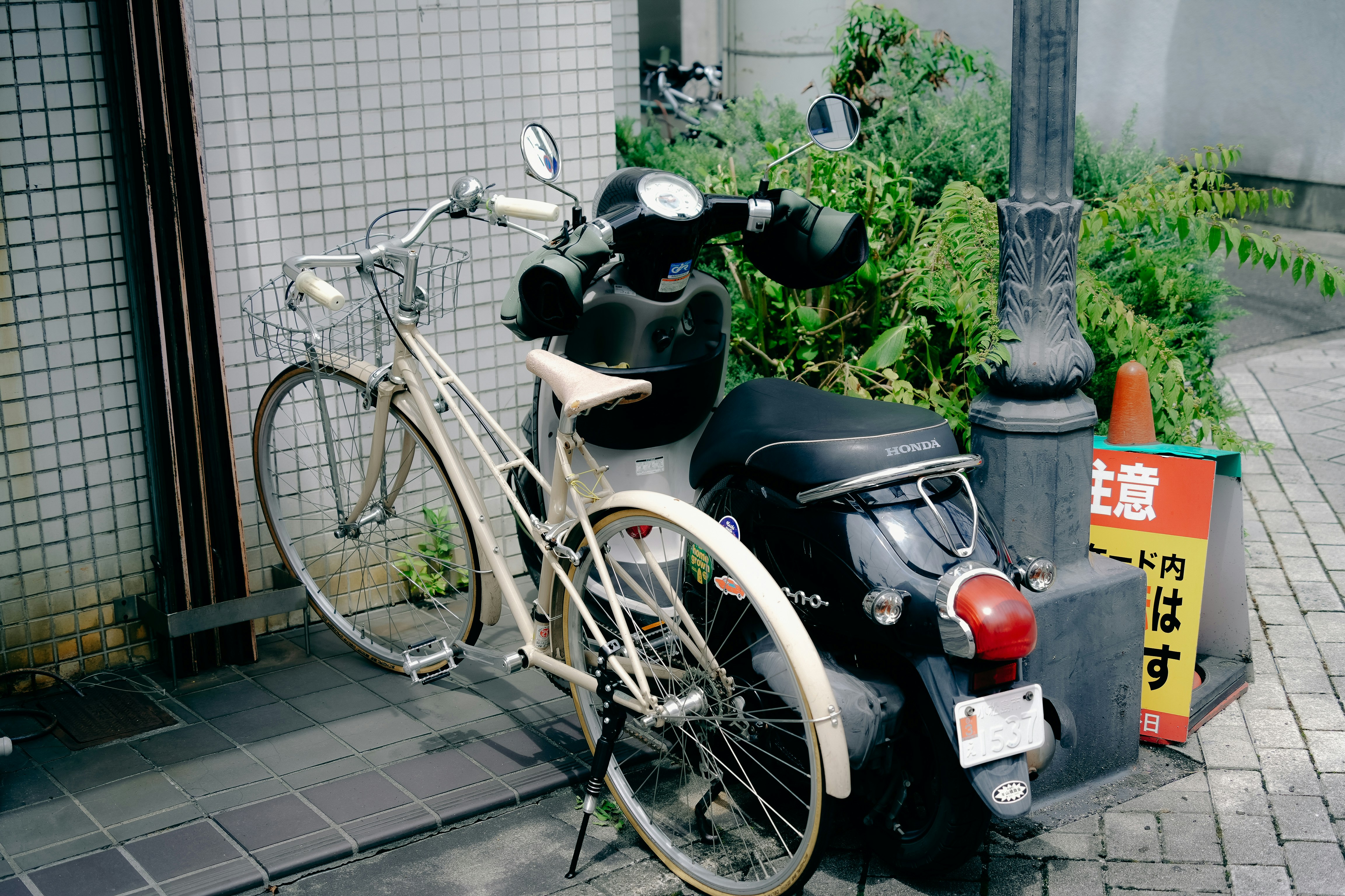 A bicycle leans against a parked scooter.