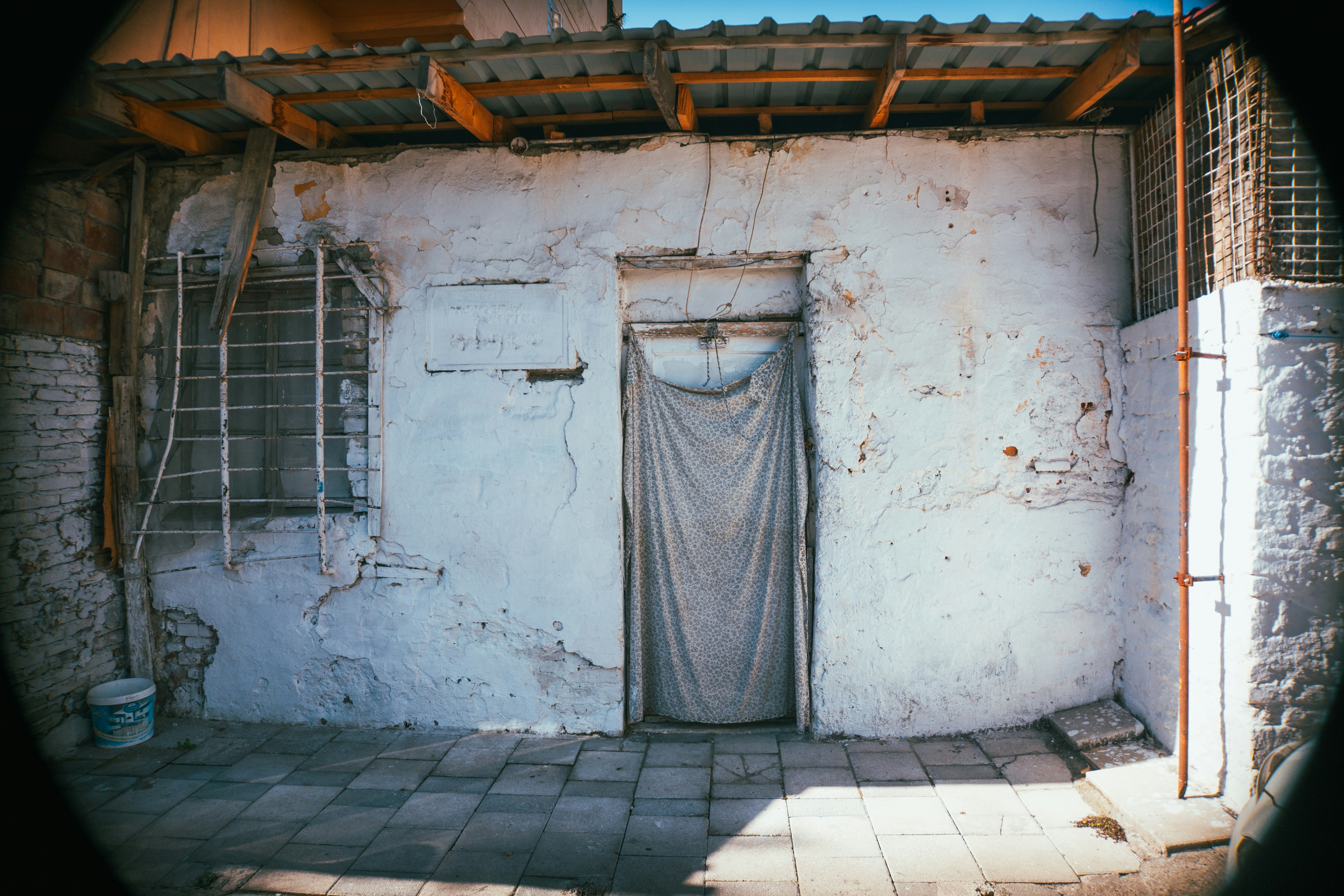 Weathered wall with a draped cloth covering an entrance, showcasing the passage of time and neglect.