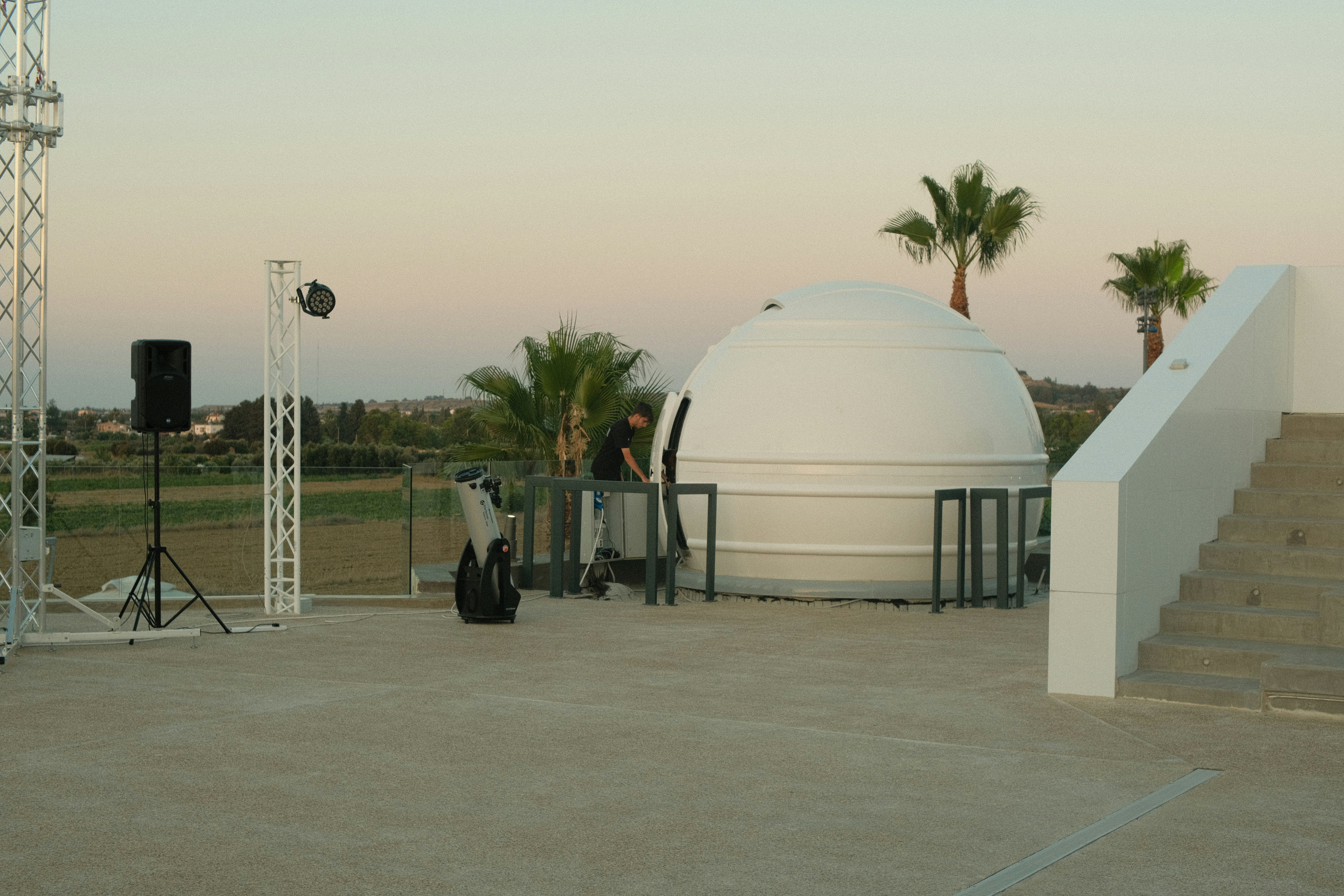 White dome structure with dj setup and palm trees.