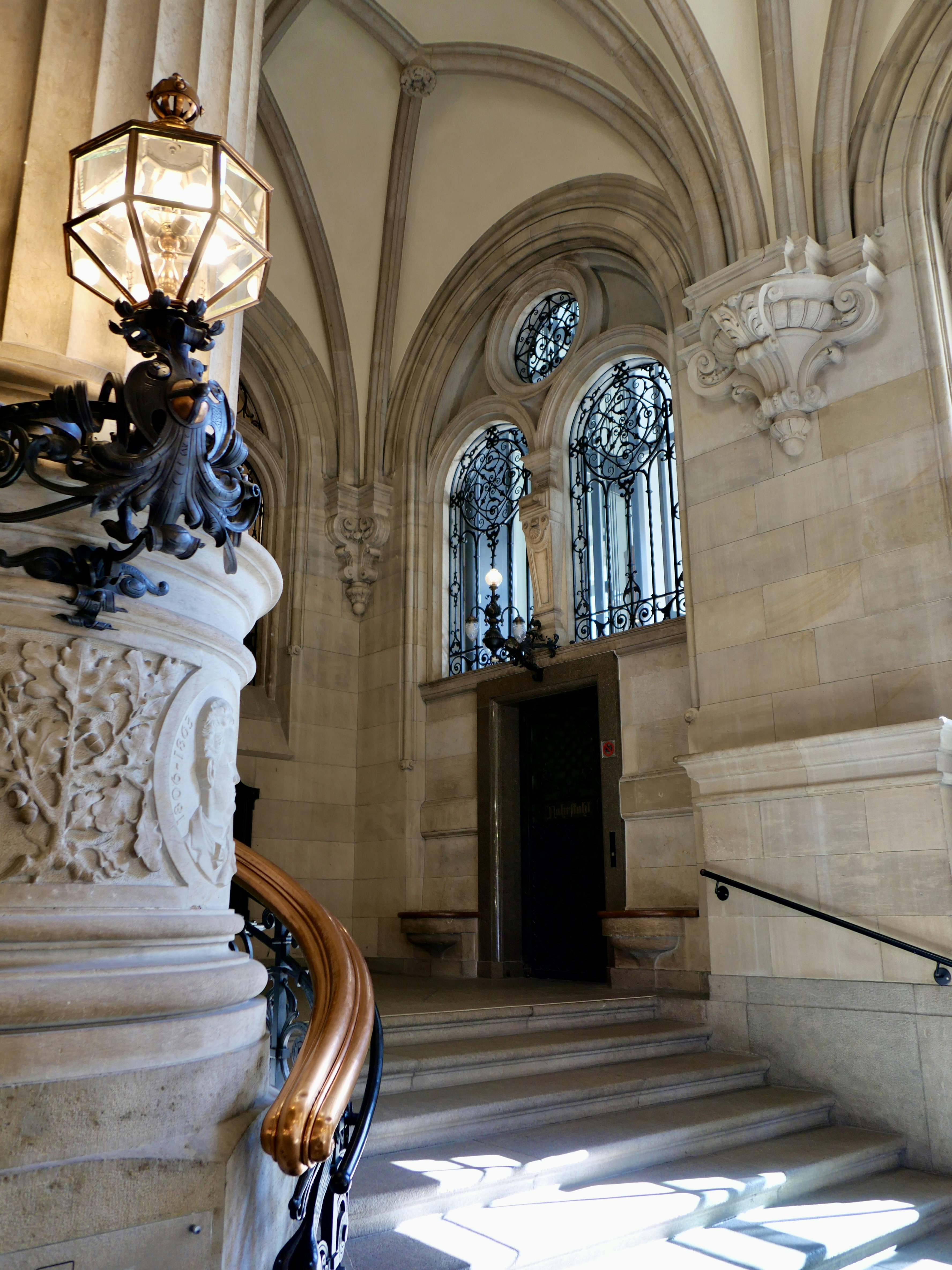 Rathaus | Ornate staircase with gothic architectural details and lamp