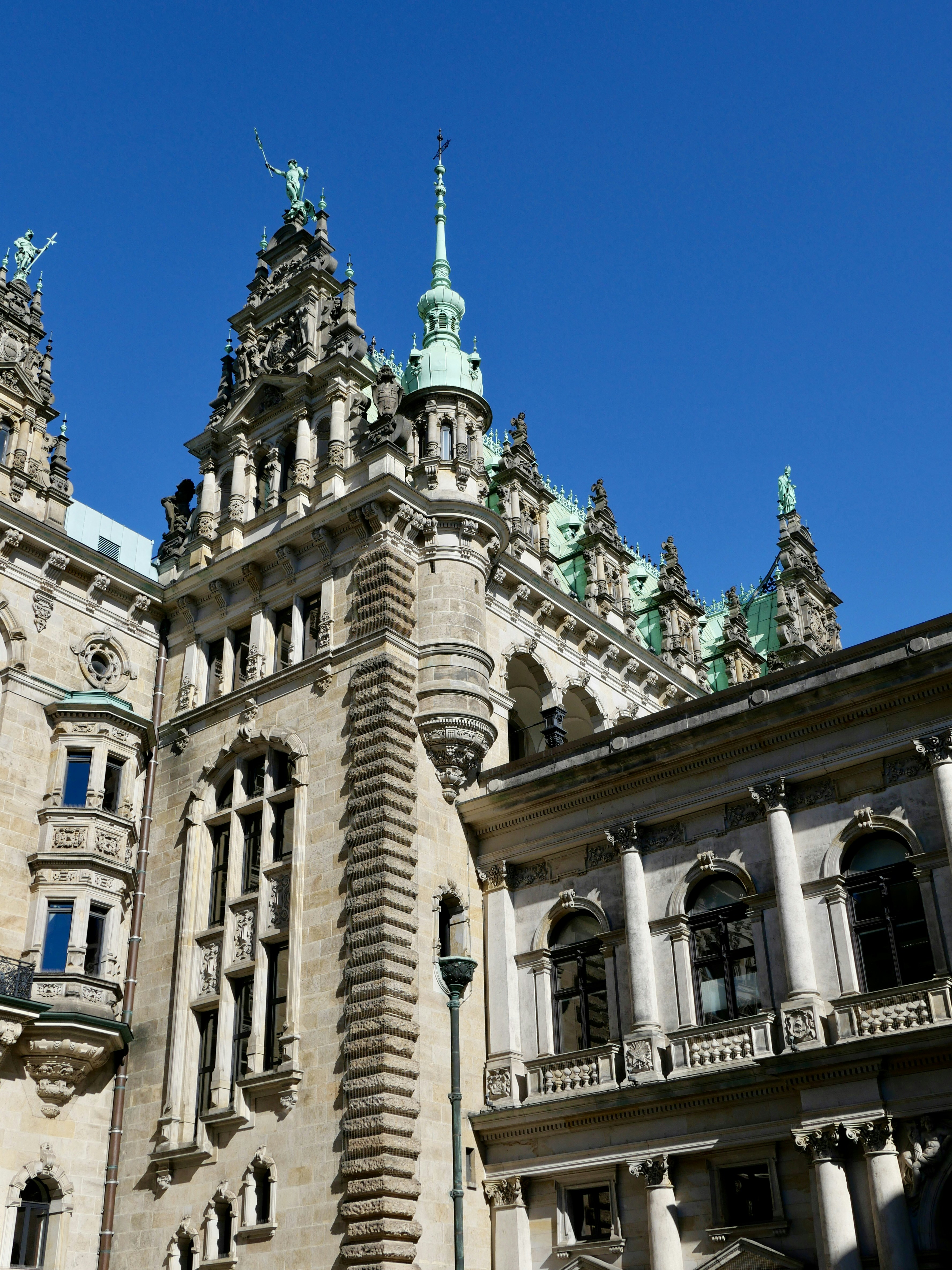 Intricate architectural details of a historic building against a clear blue sky, showcasing ornate spires and decorative elements.