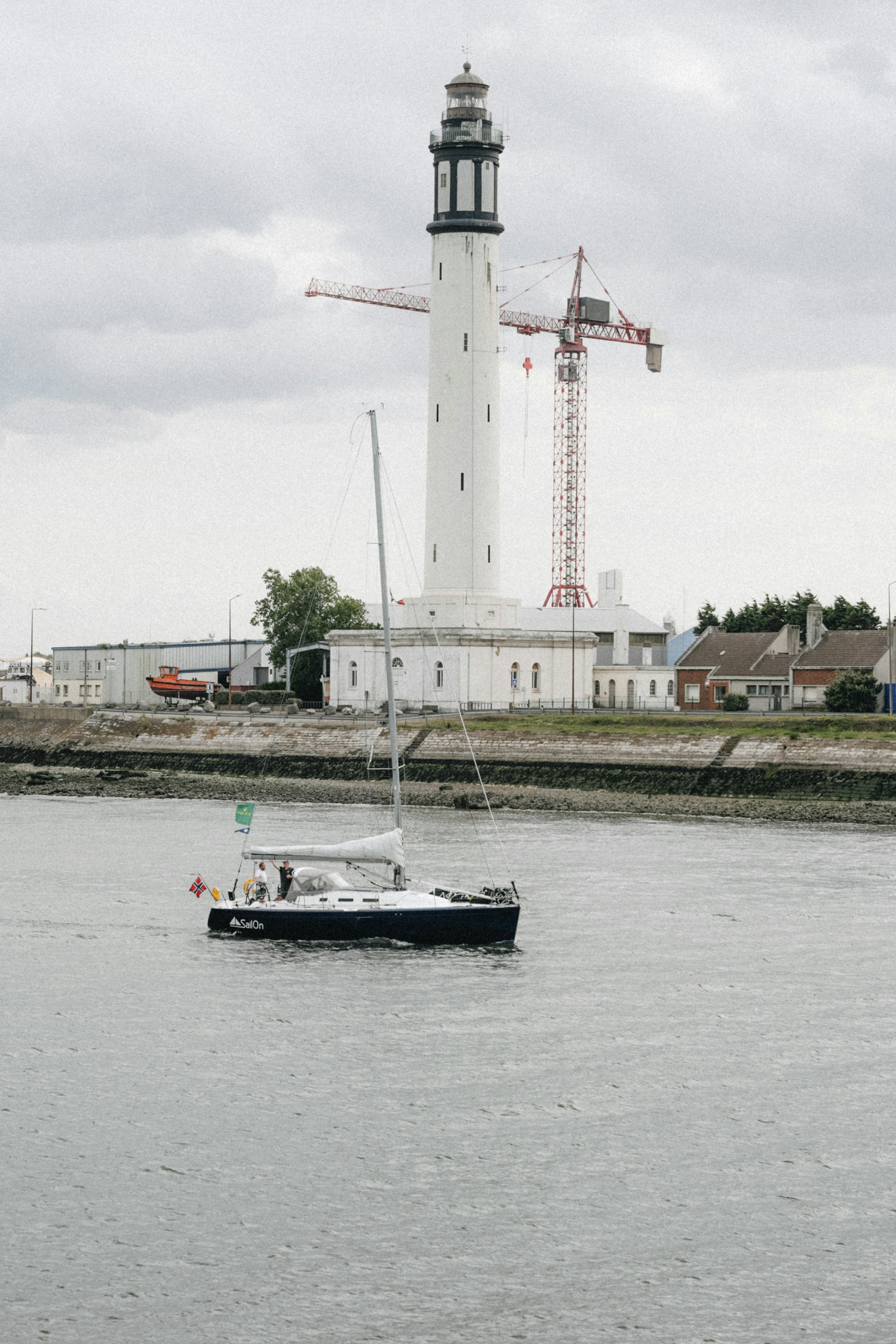 Harbor Sentinel Under Construction: Lighthouse, Crane, and a Quiet Sail