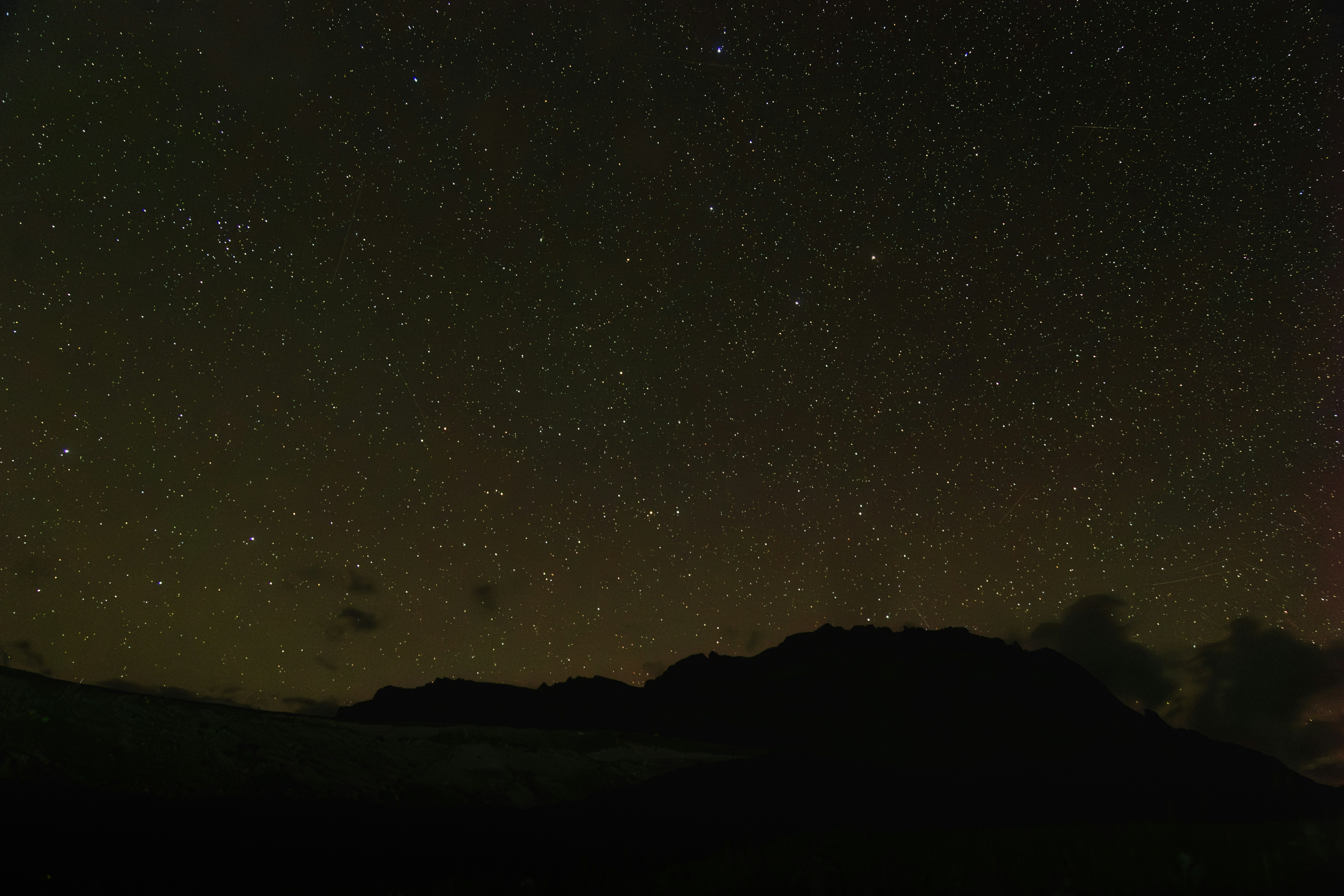 Starry night sky over dark hills
