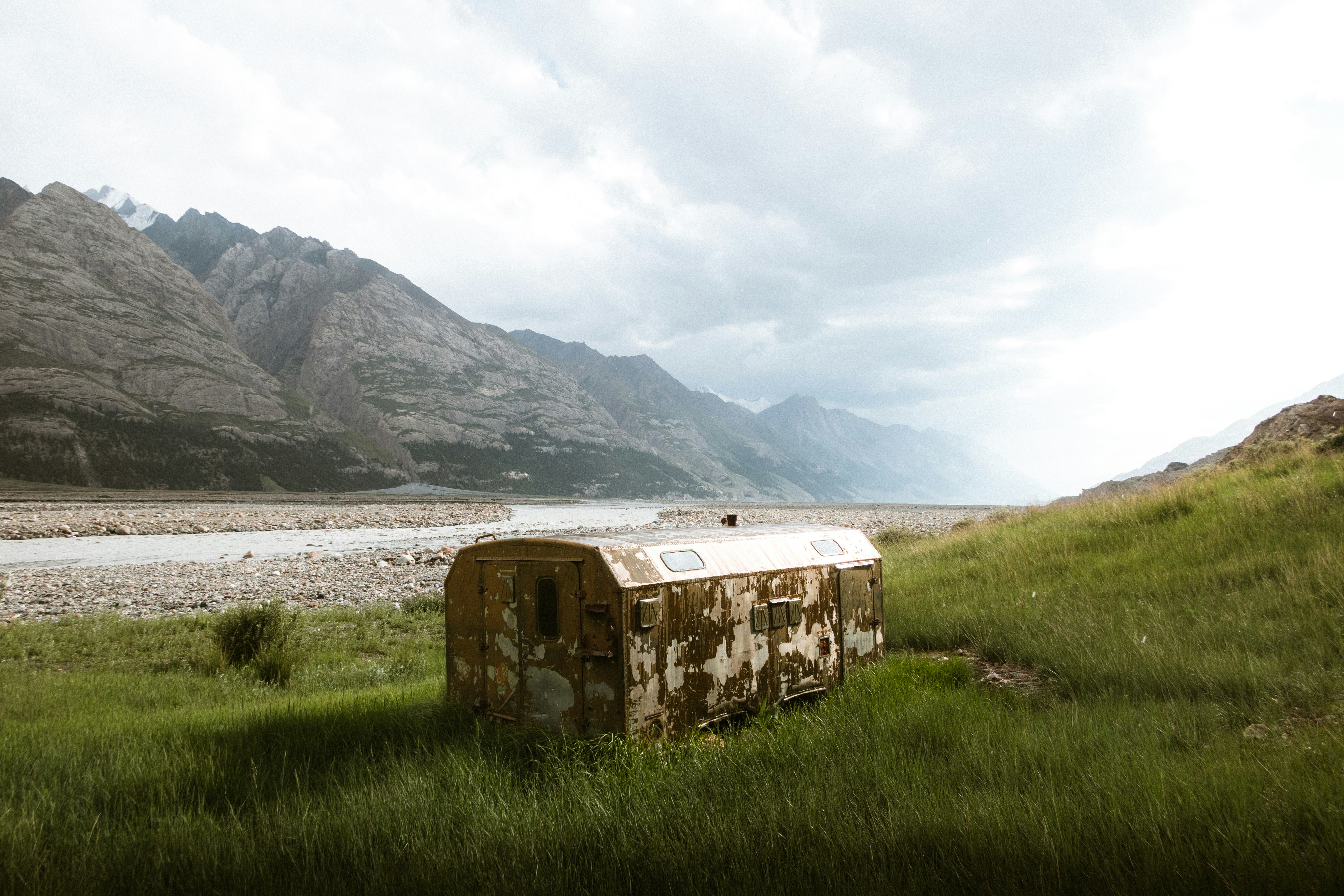 Abandoned trailer in grassy field with mountains