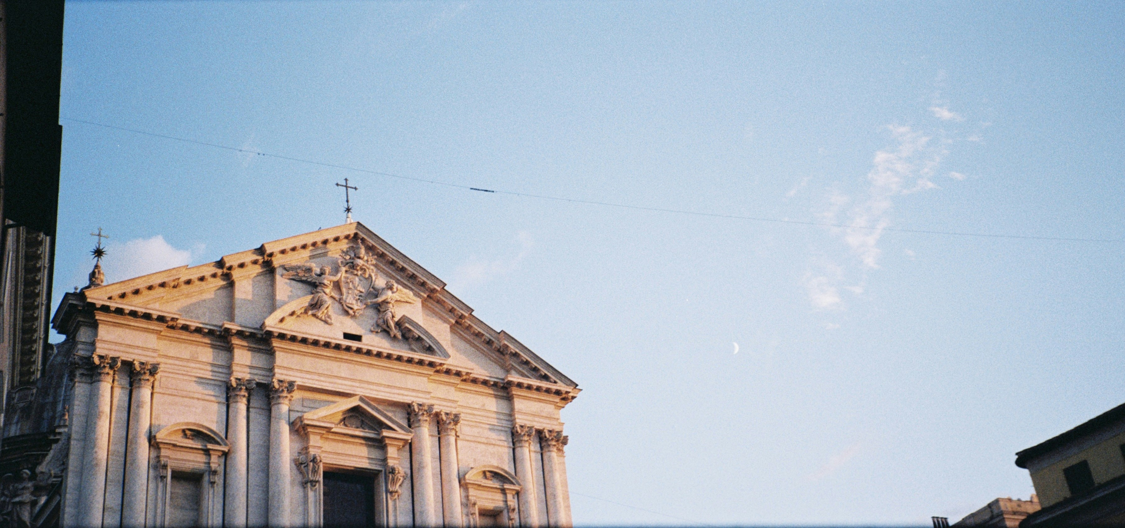 church in with the sunset shining on it in rome with a blue sky. | Ornate building facade against a clear blue sky