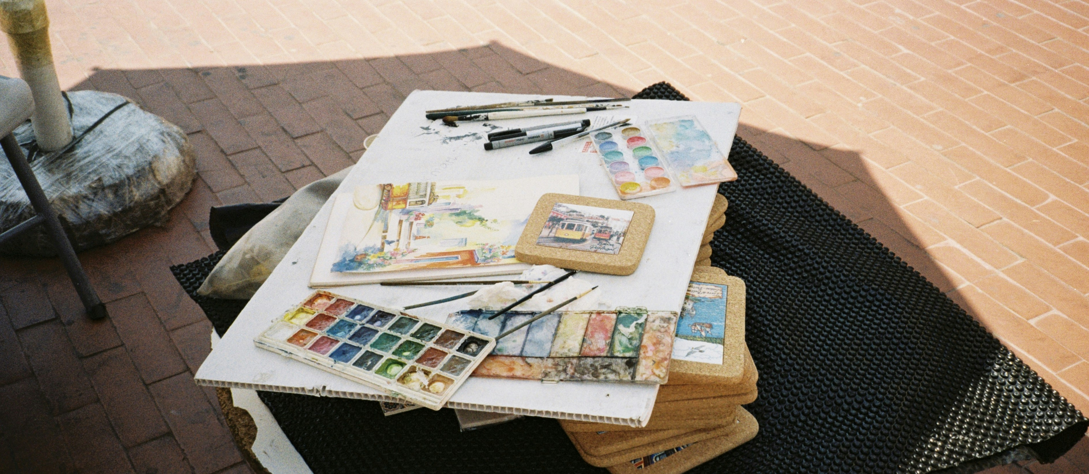 watercolour art found in the streets of lisbon. | Art supplies including watercolors, brushes, and sketchpads laid out.