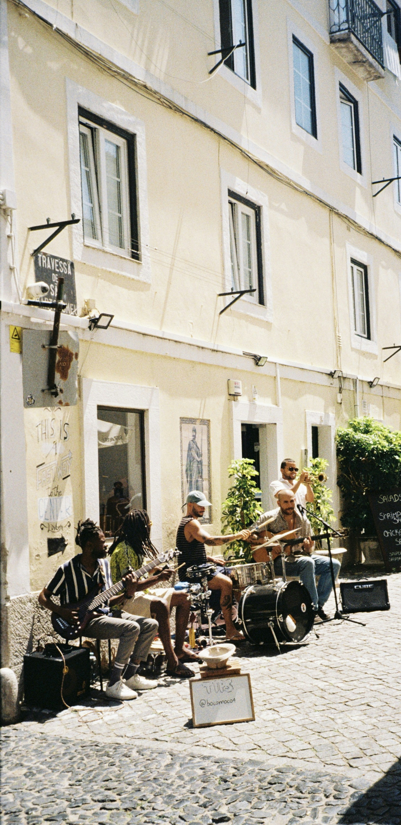 street musicians playing outside in lisbon | A band plays music on a cobblestone street.