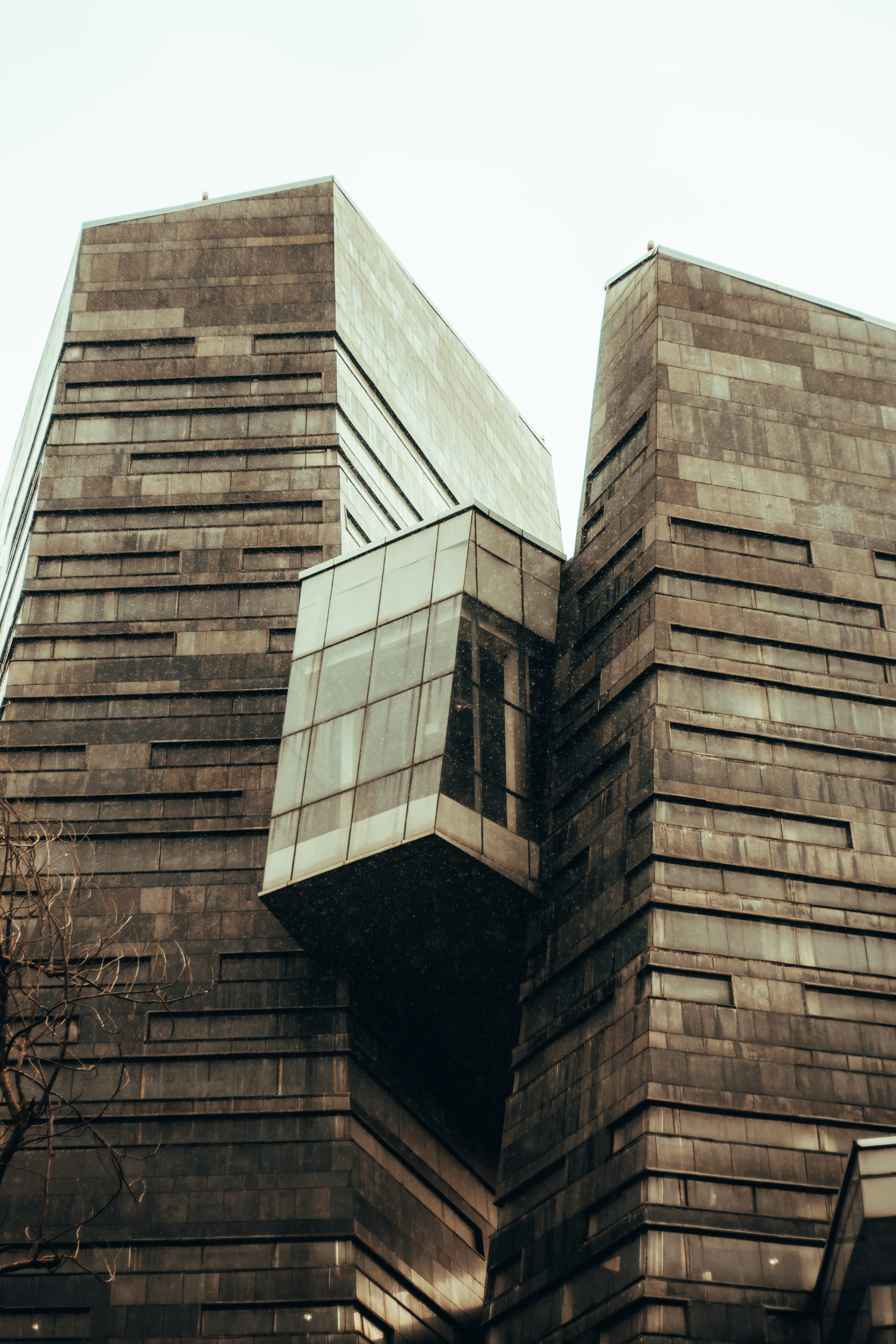 A modern architectural structure featuring sharp angles and a cantilevered glass section, showcasing innovative design elements against a muted sky.