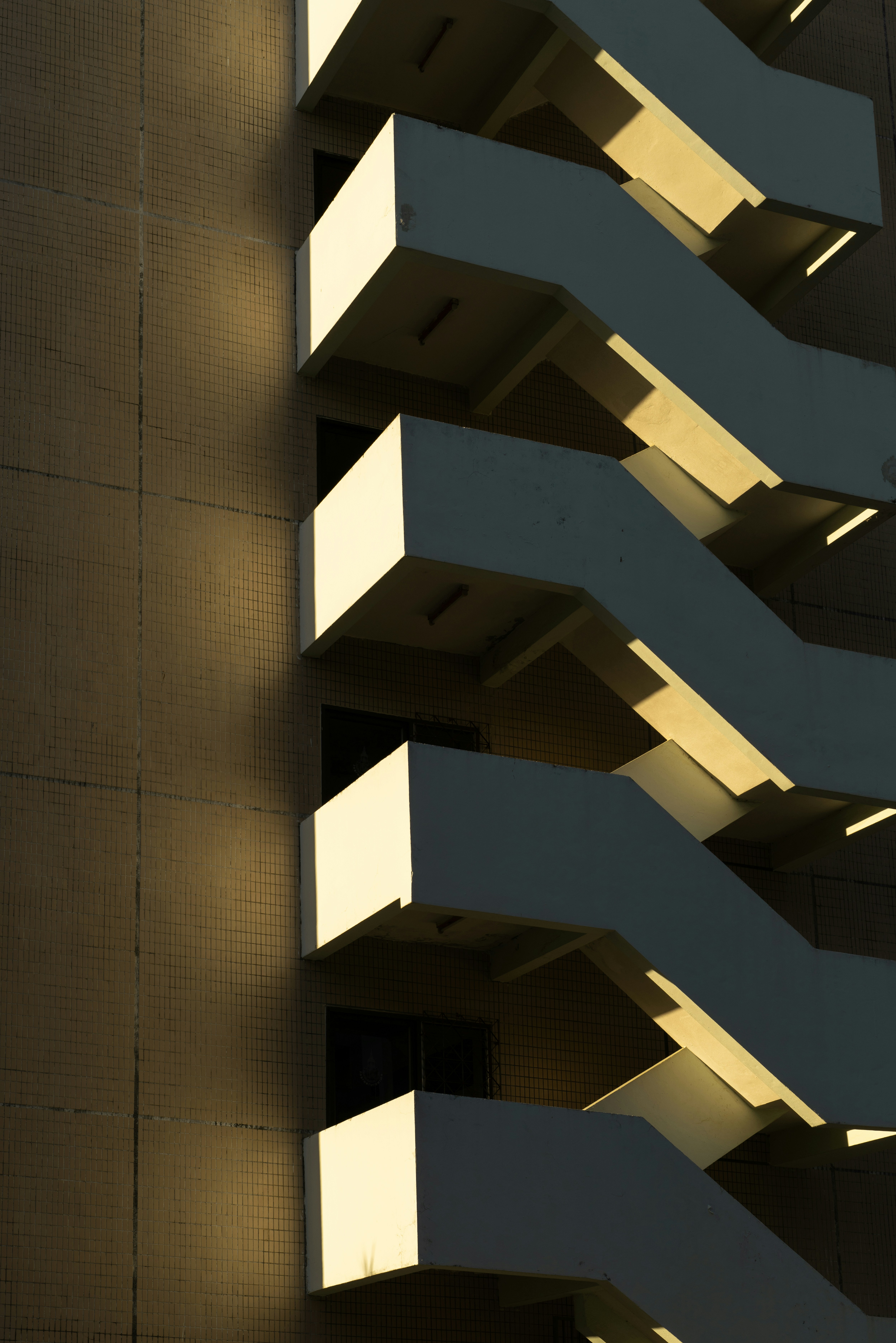 Abstract view of a building's stairwell, showcasing geometric shapes and the interplay of light and shadow on the surfaces.