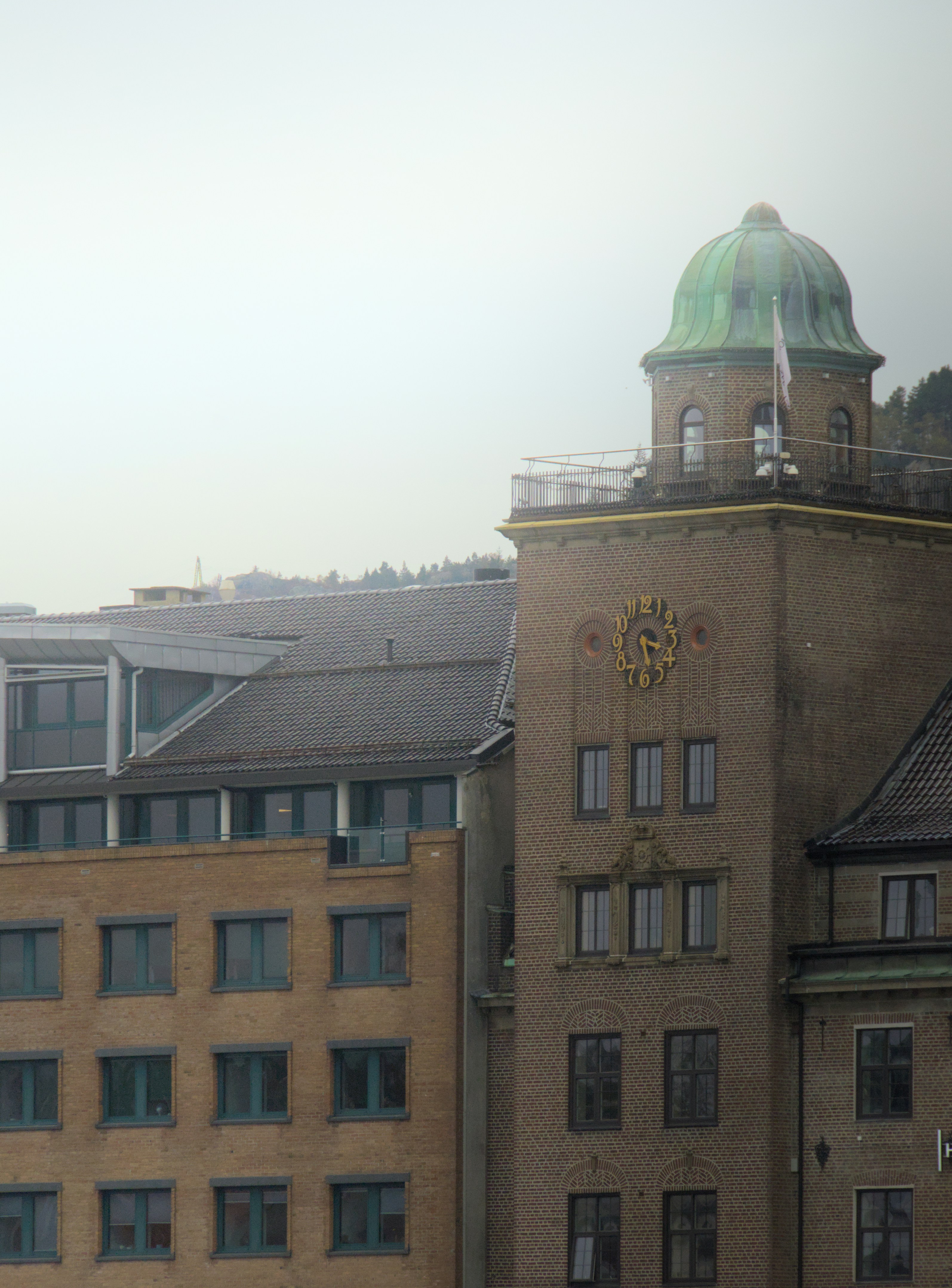 Historic clocktower adorned with a green dome, surrounded by modern architecture. The clock displays the time, hinting at a blend of past and present.