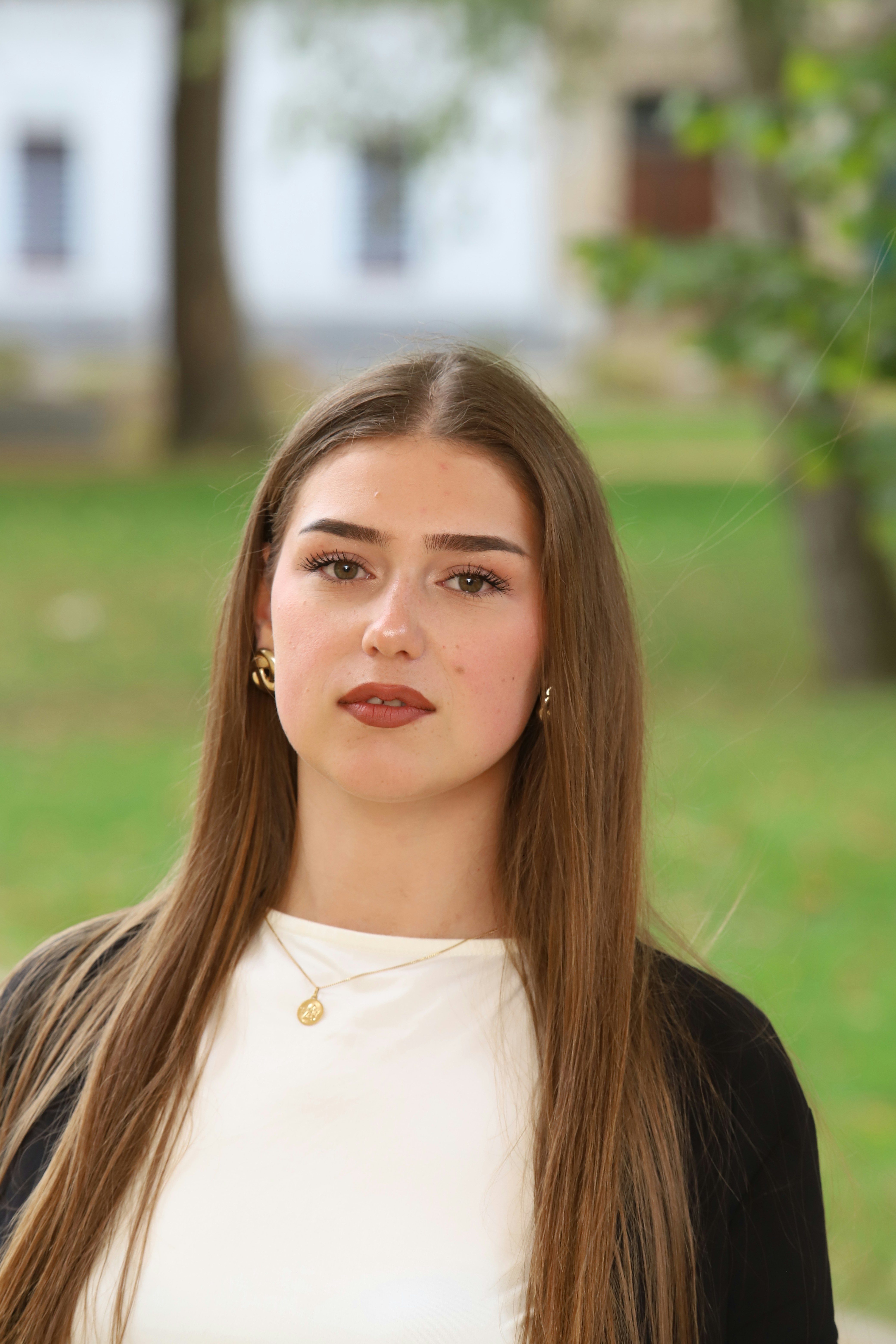 Young woman with long brown hair wearing jewelry.