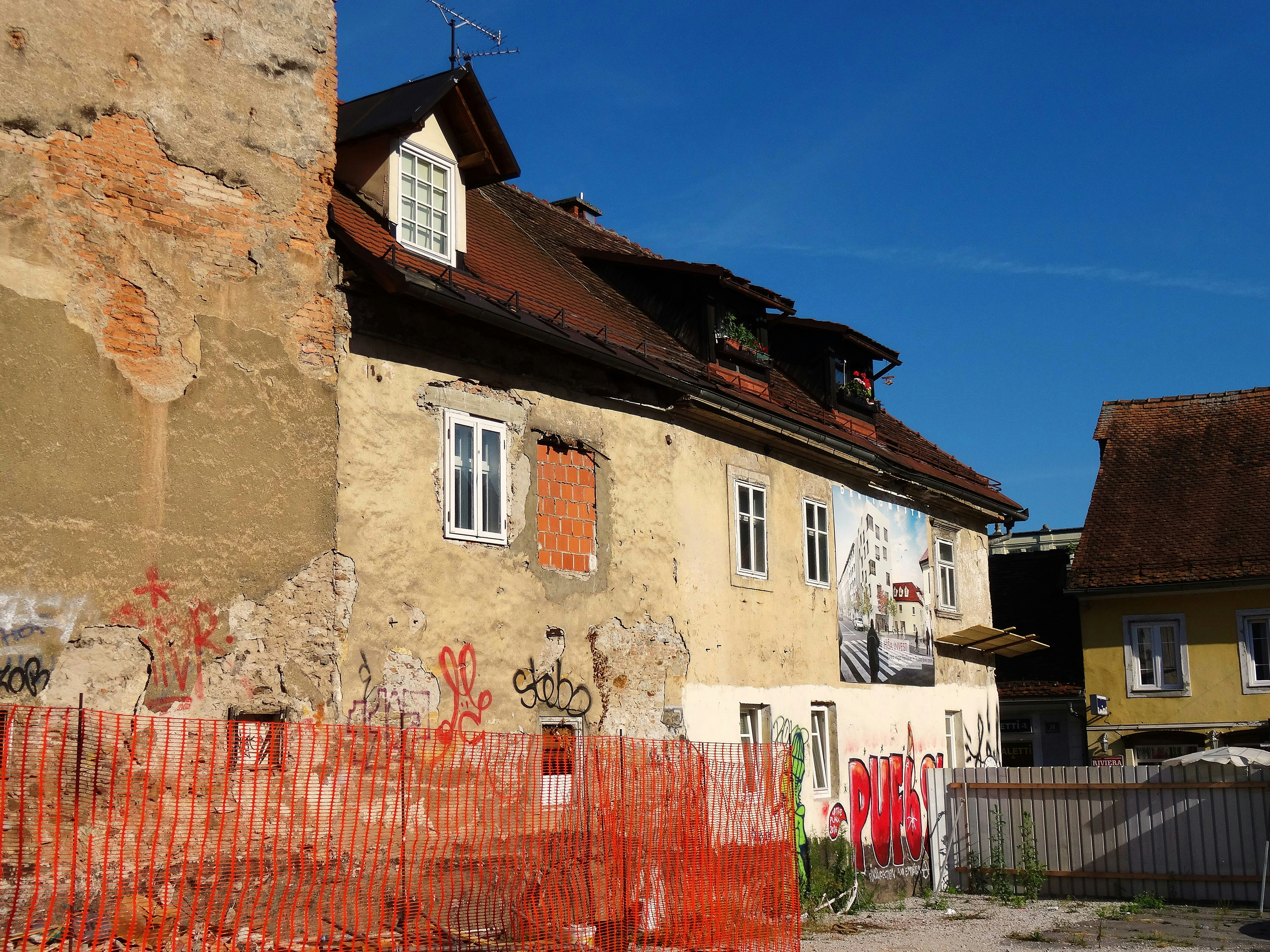Old building with graffiti and orange construction fence.