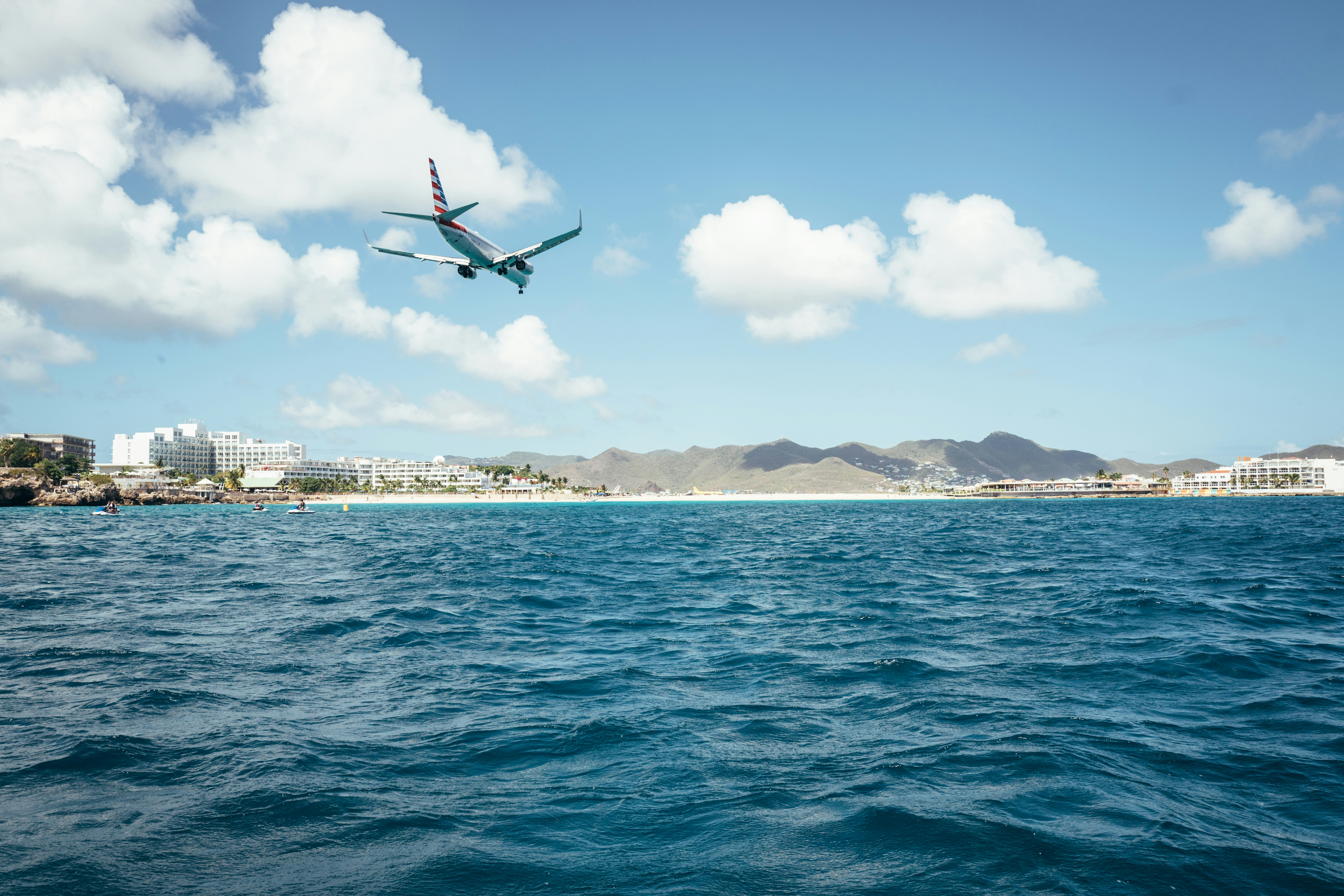 Airplane flying over the ocean towards land.