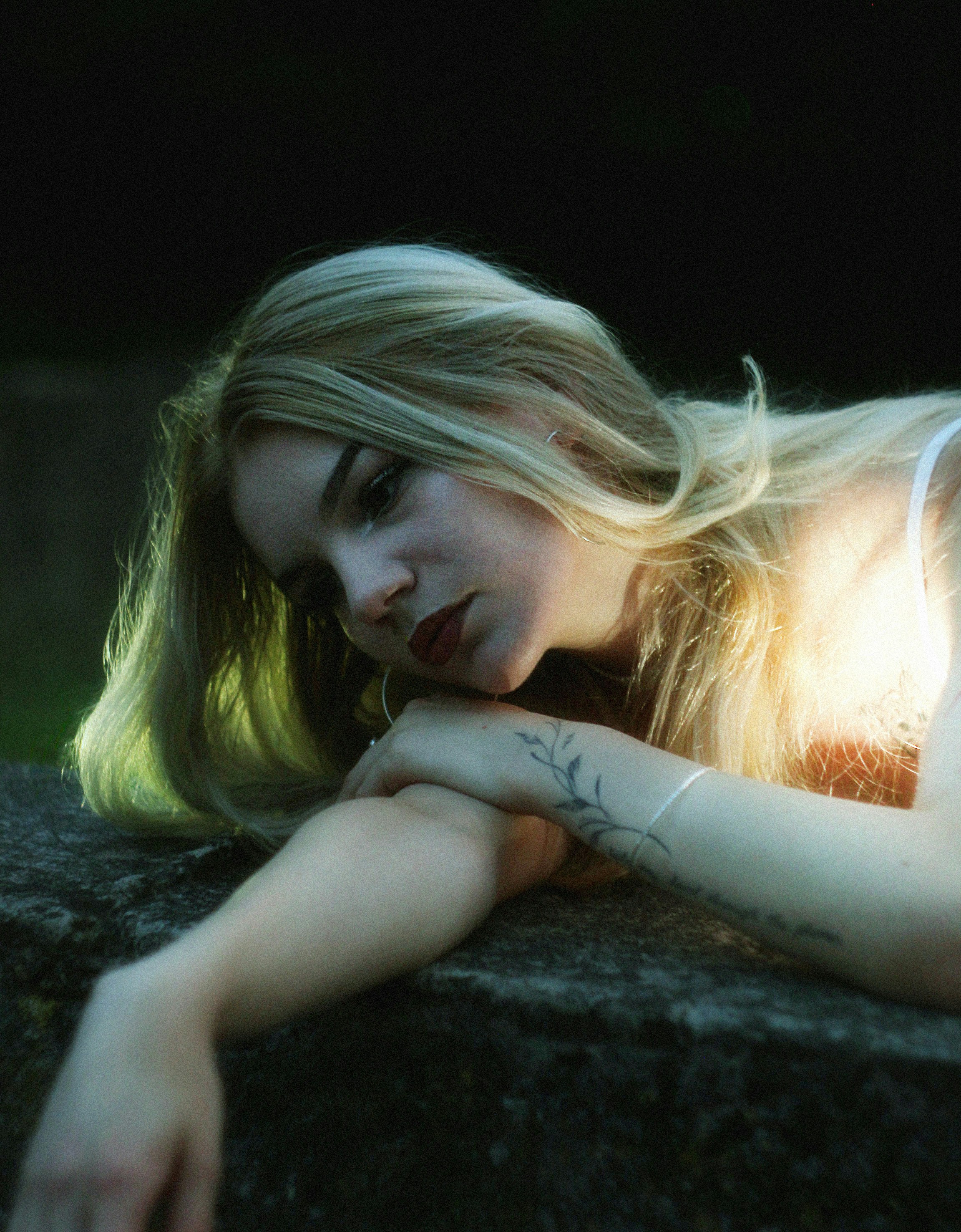 A young woman with blonde hair rests her head.