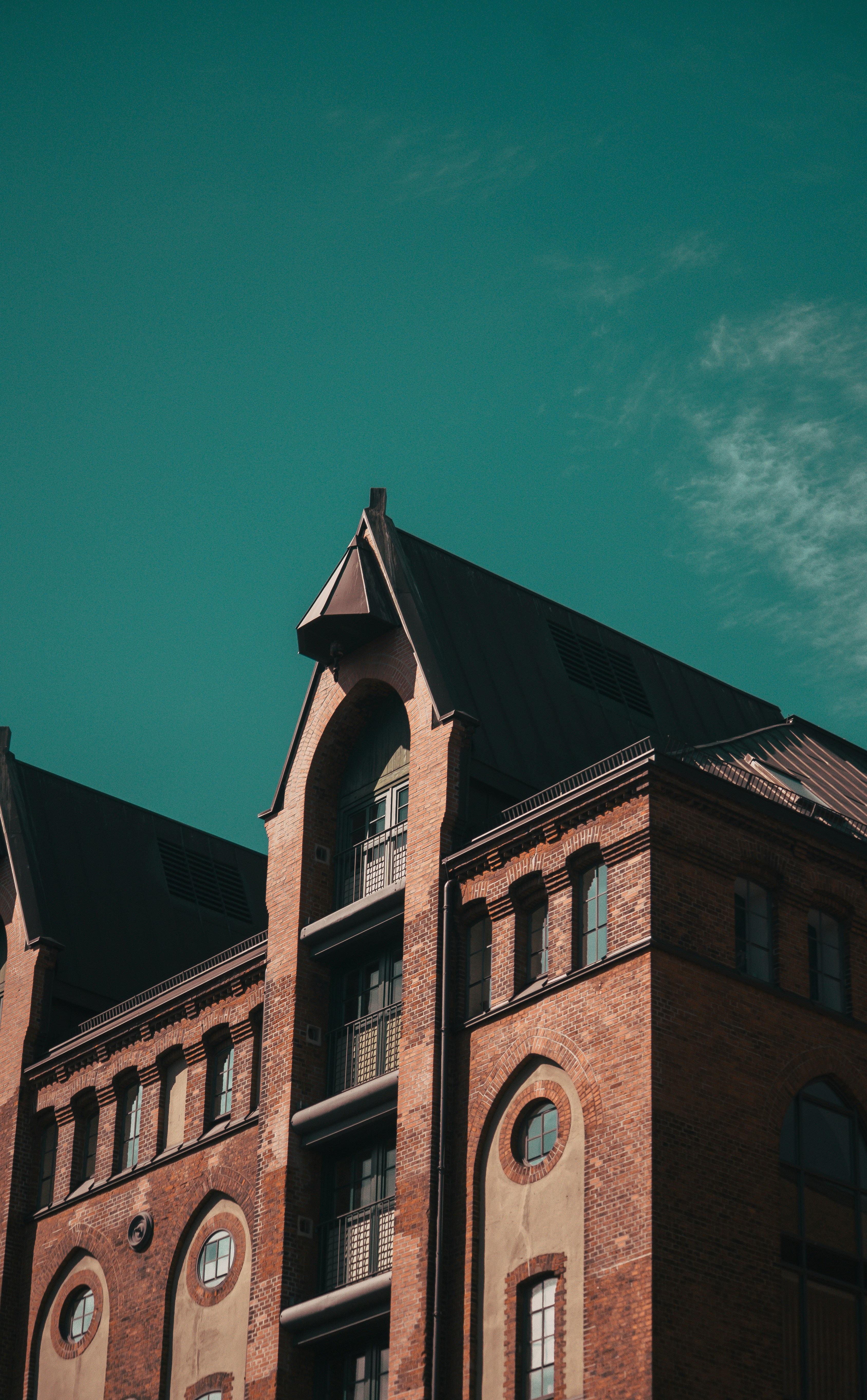Brick building with arched windows under a teal sky