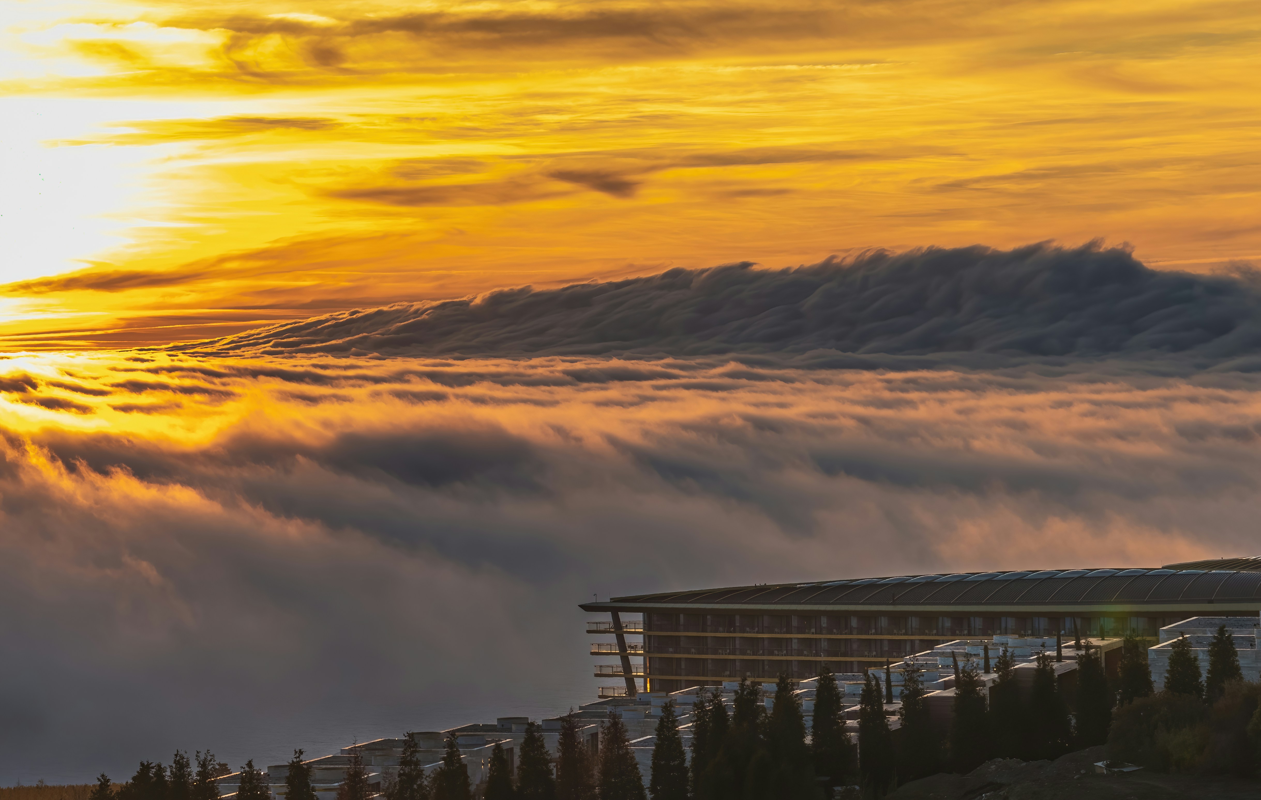 Golden sunset over a sea of clouds with building.