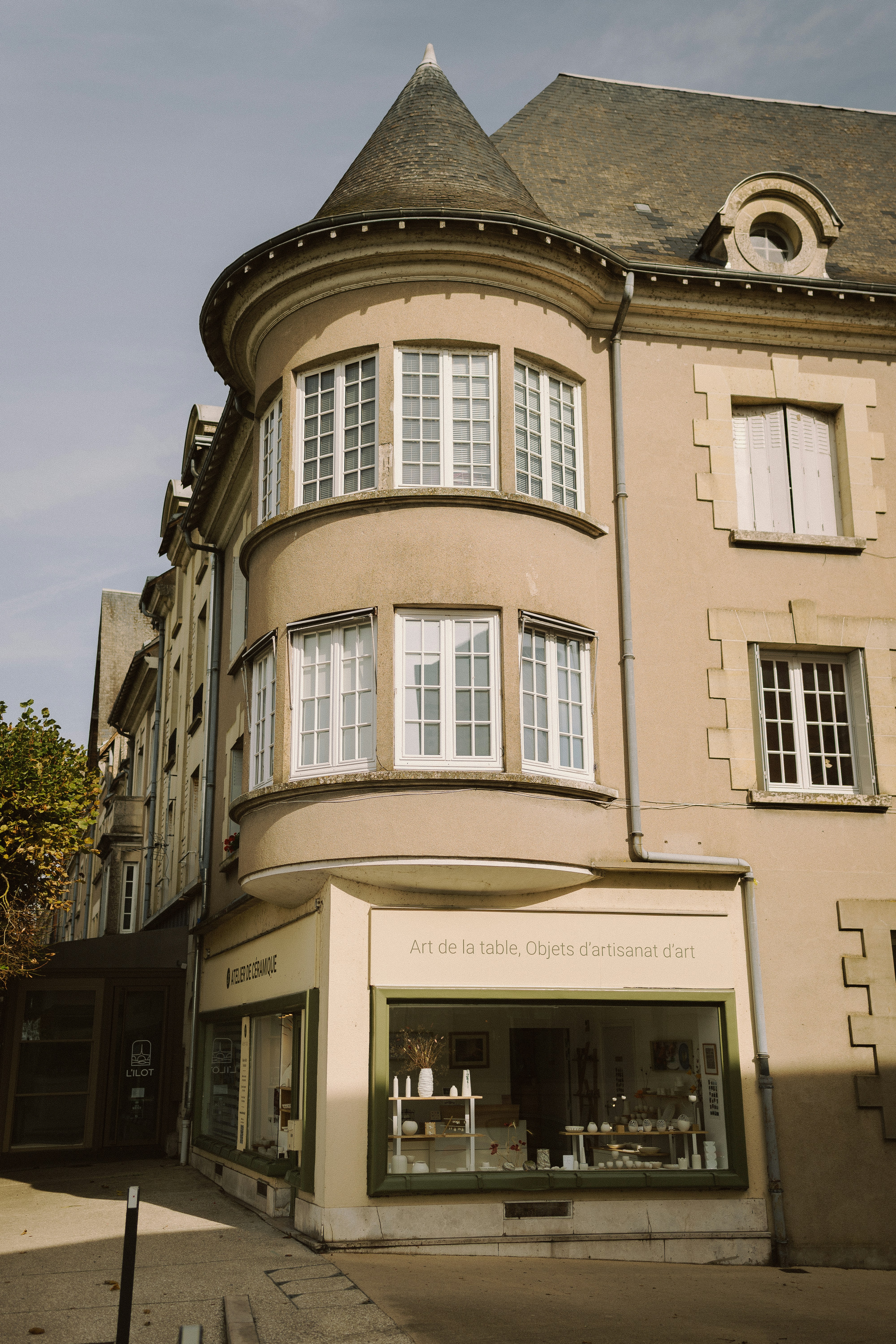 Charming building showcasing a curved facade and large windows, with an artful shop display visible through the glass. The scene reflects a blend of classic and modern architectural styles.
