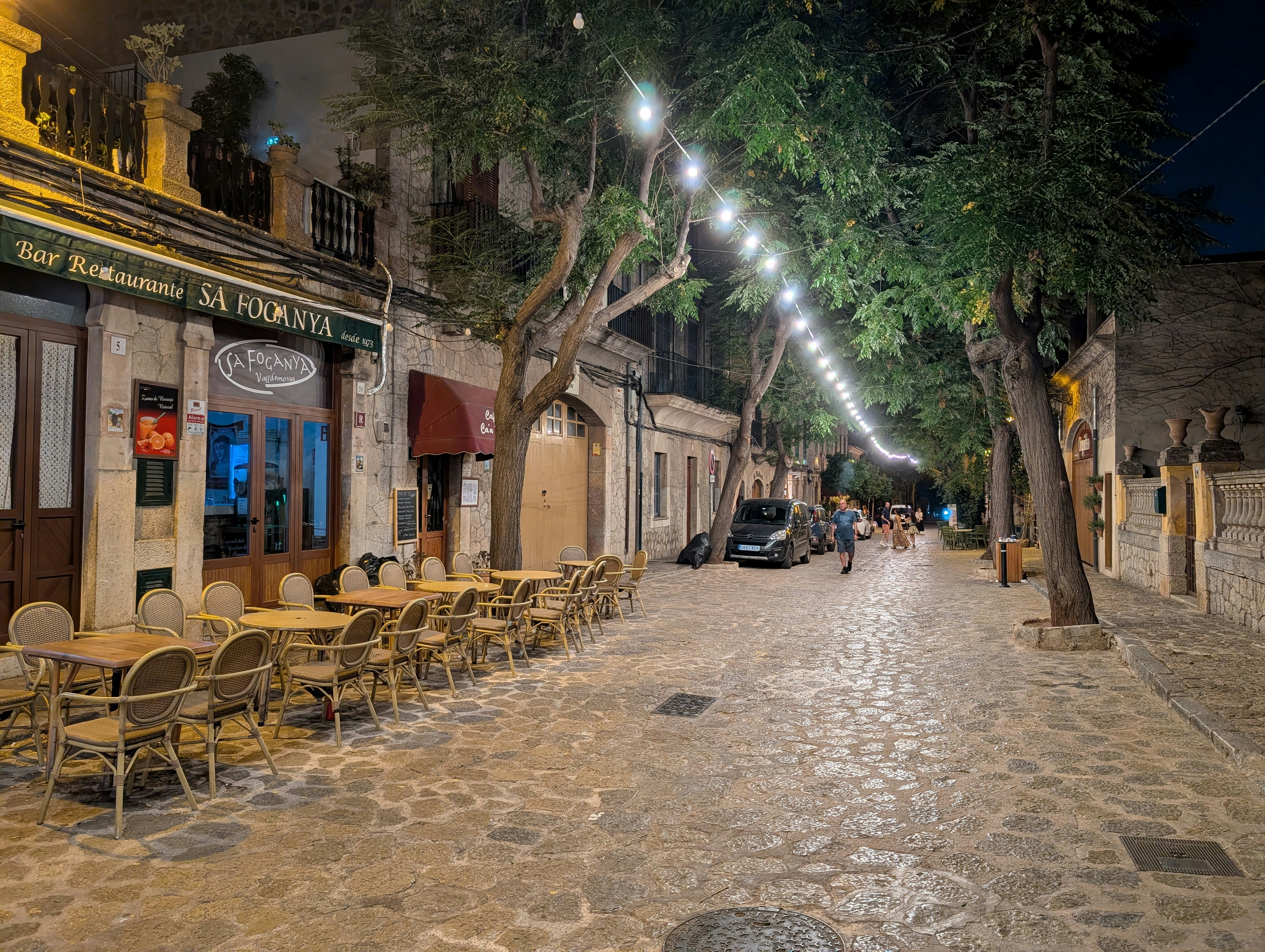 Street cafe with tables and string lights at night