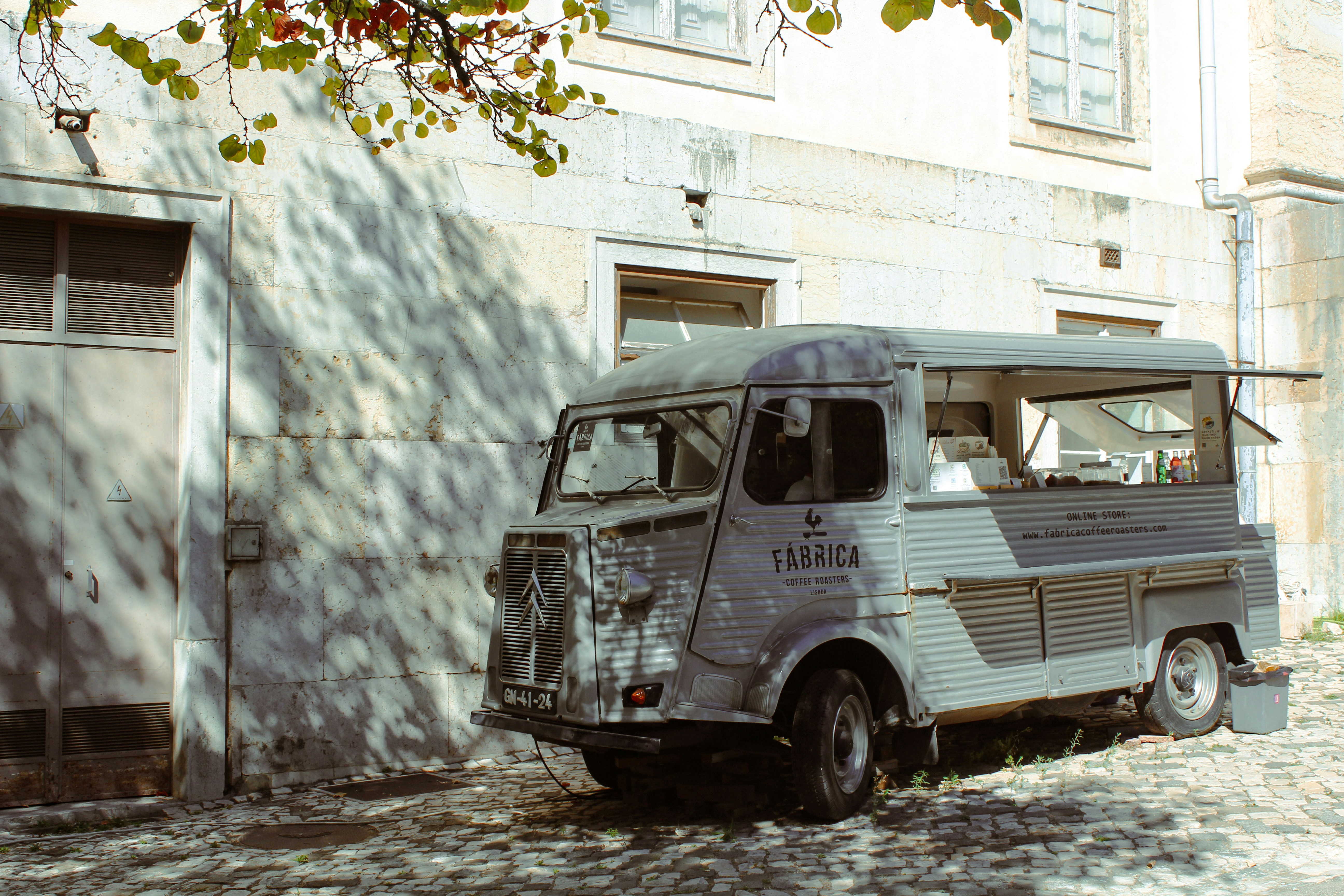 An old grey van parked by a building.