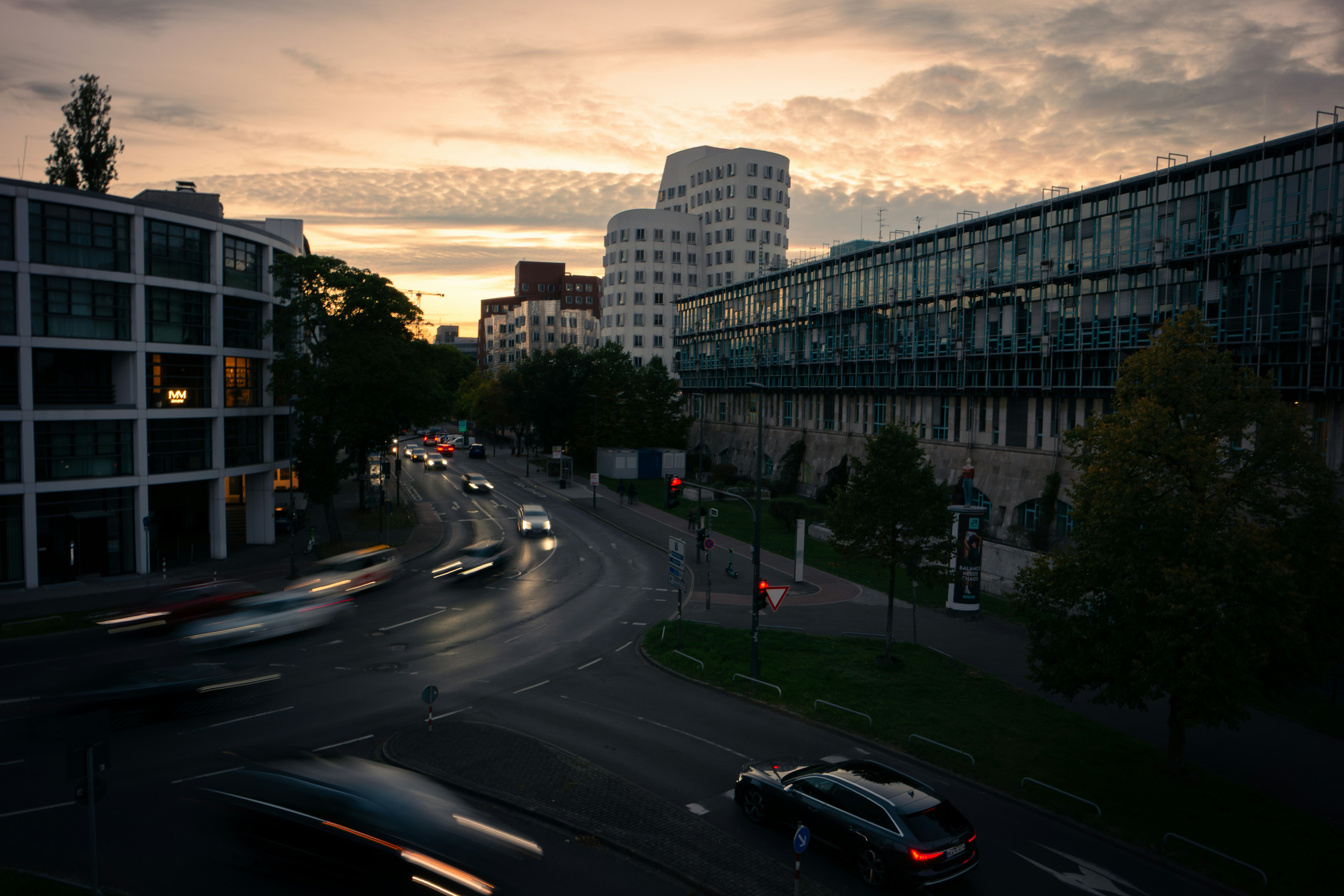 Cars driving on a city street at dusk.