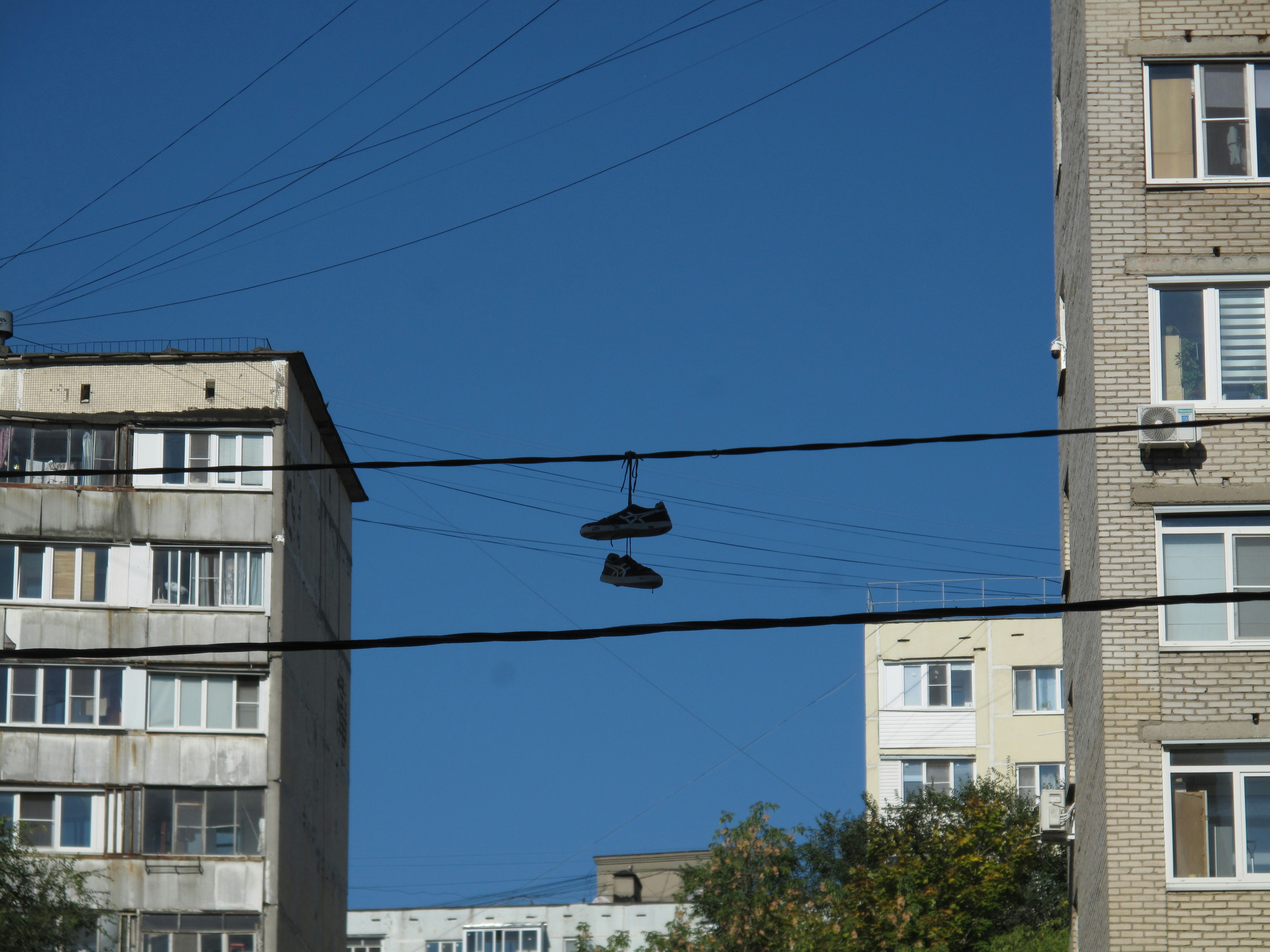 Shoes hanging on a wire between buildings.
