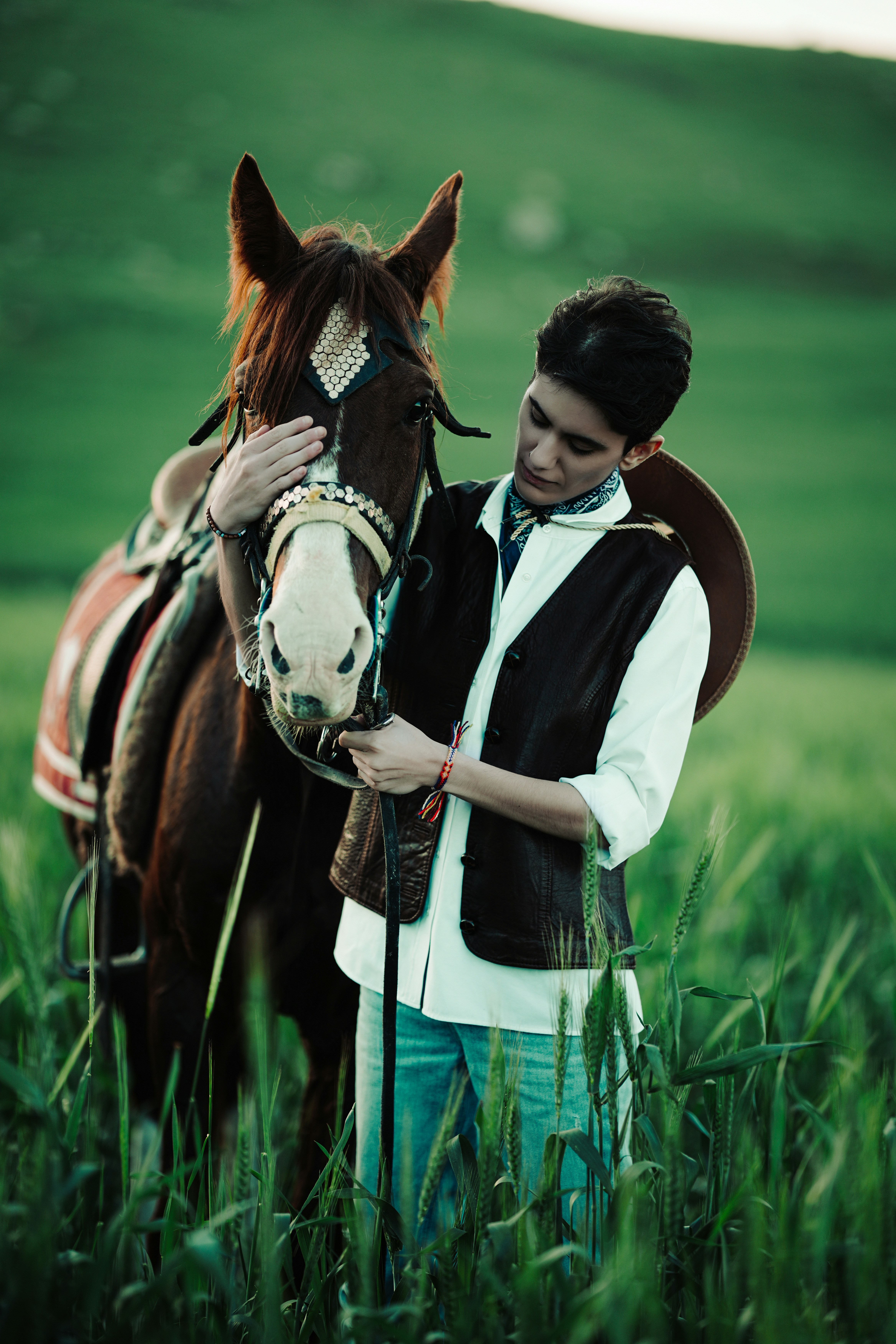 A young rider gently caresses a horse in a lush green field, showcasing their deep connection and the serene beauty of nature.