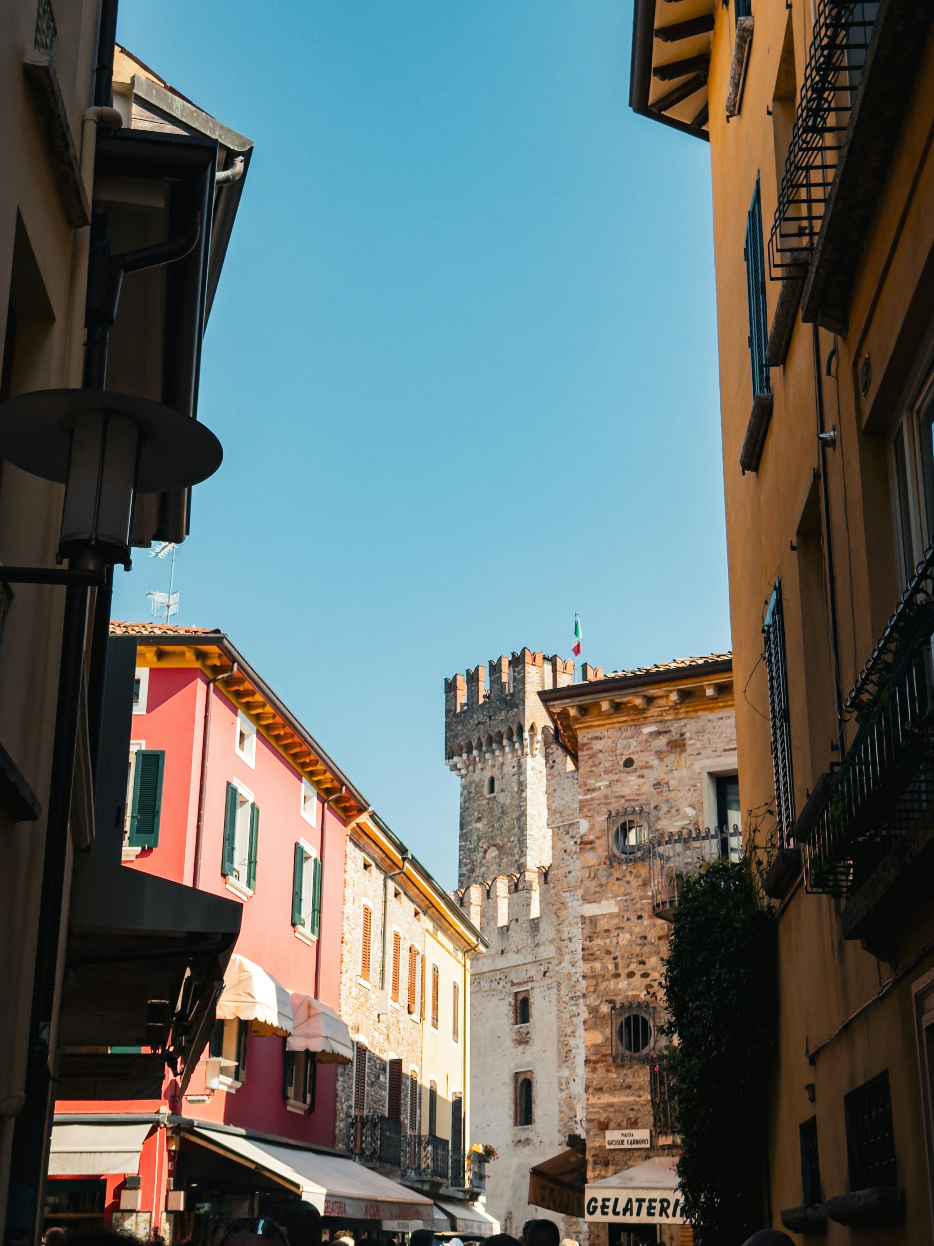 Narrow street with colorful buildings and a tower.