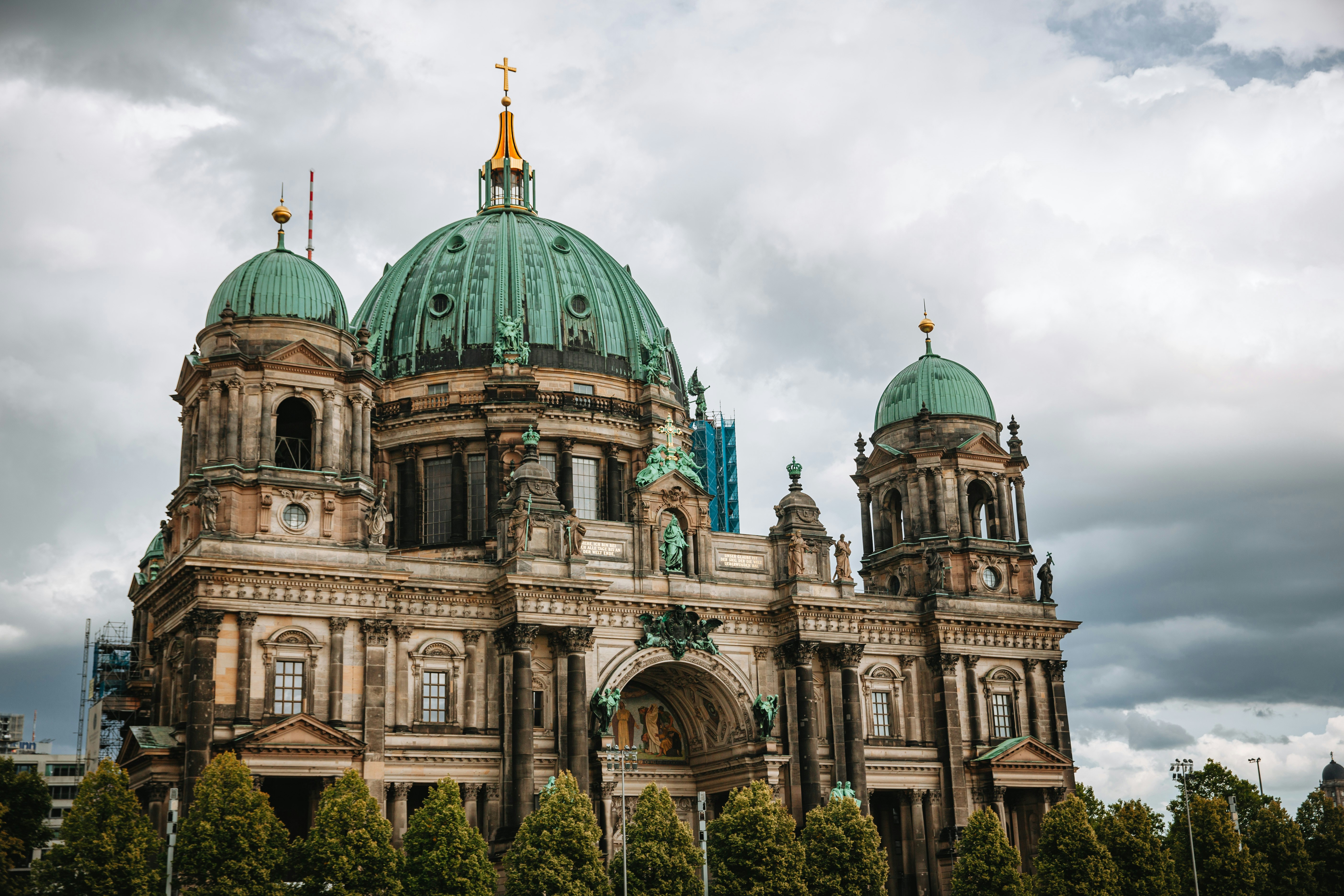 Grand cathedral with green domes under cloudy sky