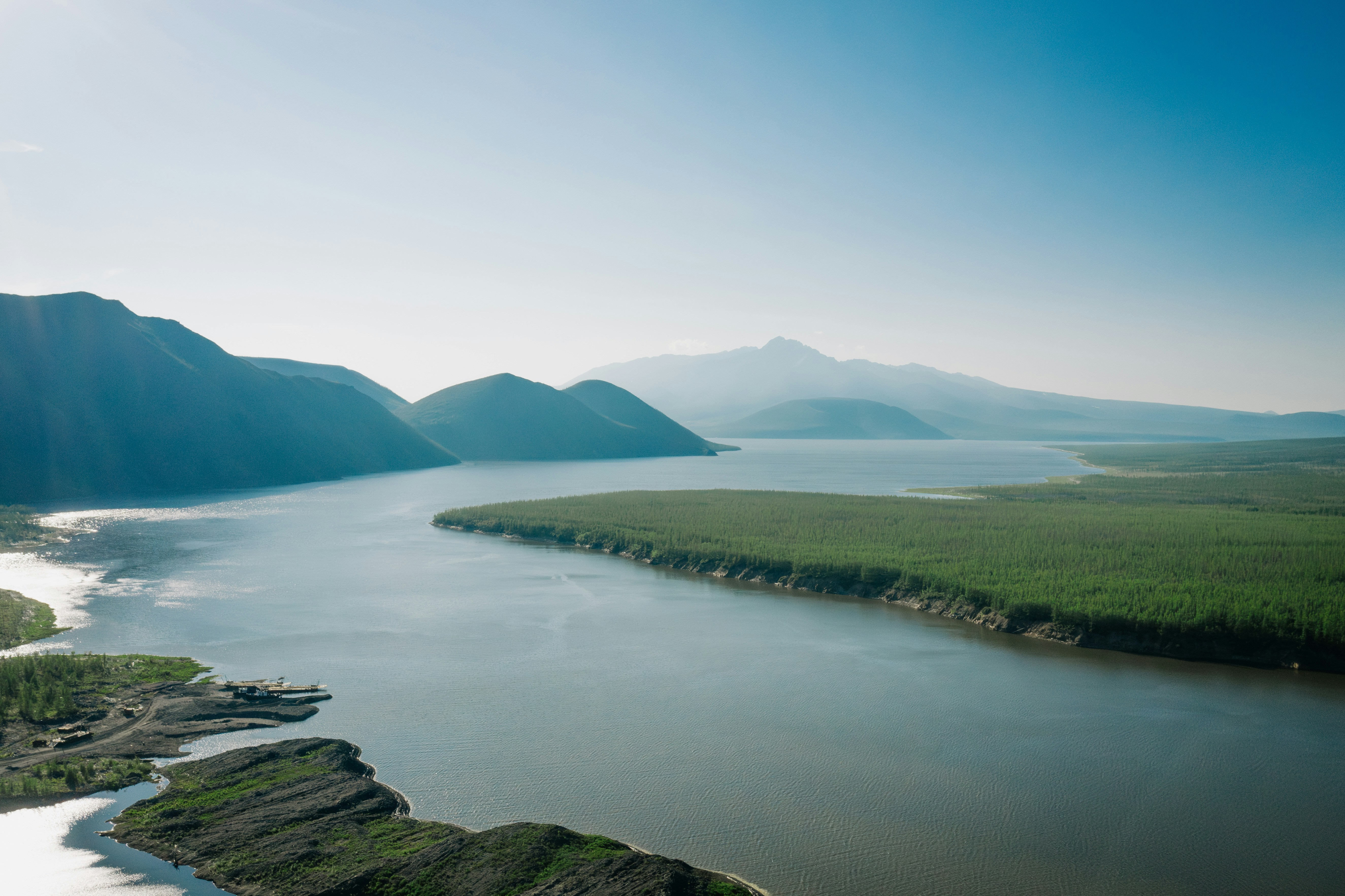 Wide river flows through green forest and mountains.
