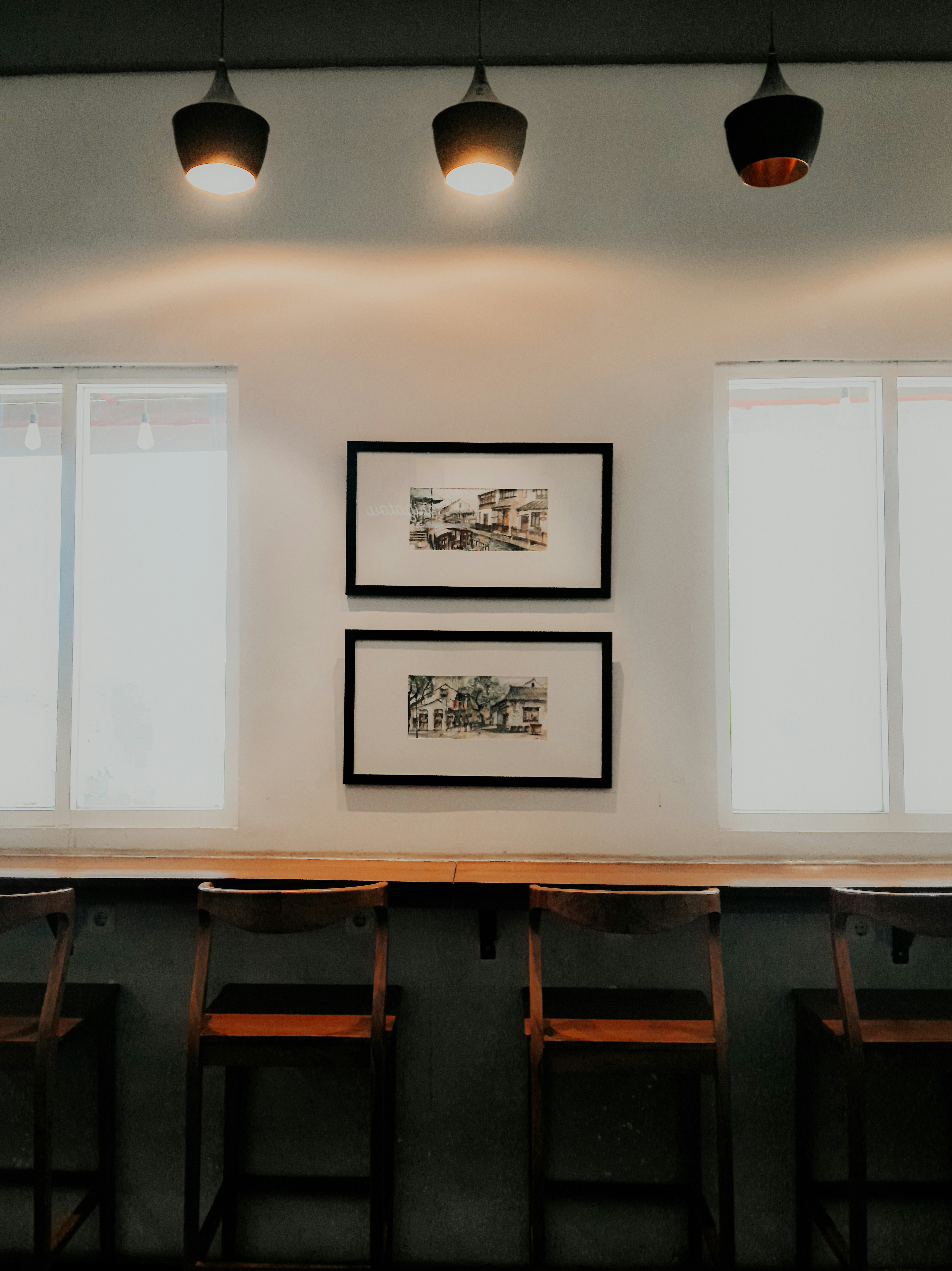 Two framed artworks hang above bar stools.