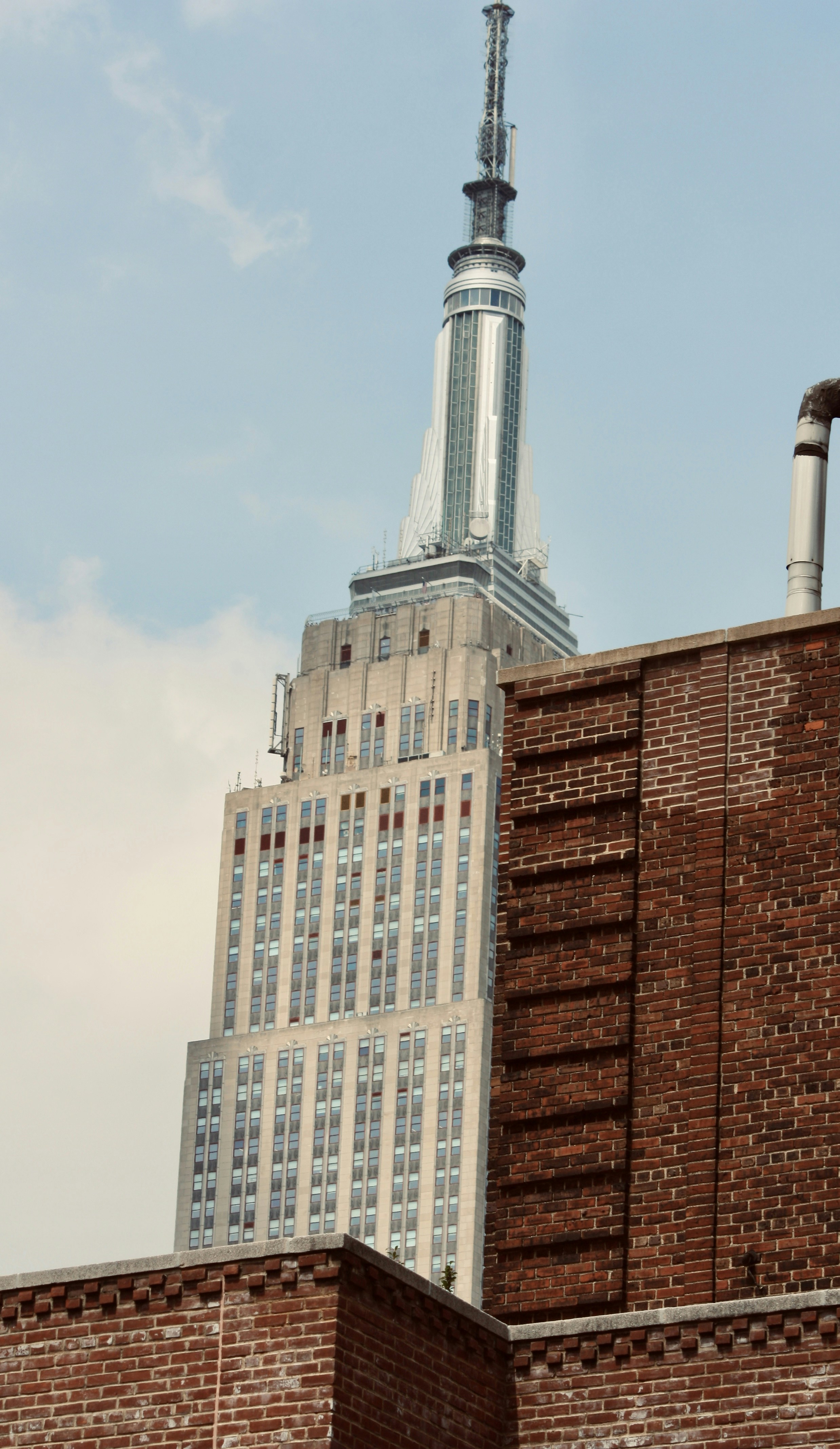 Empire state building seen between brick buildings.