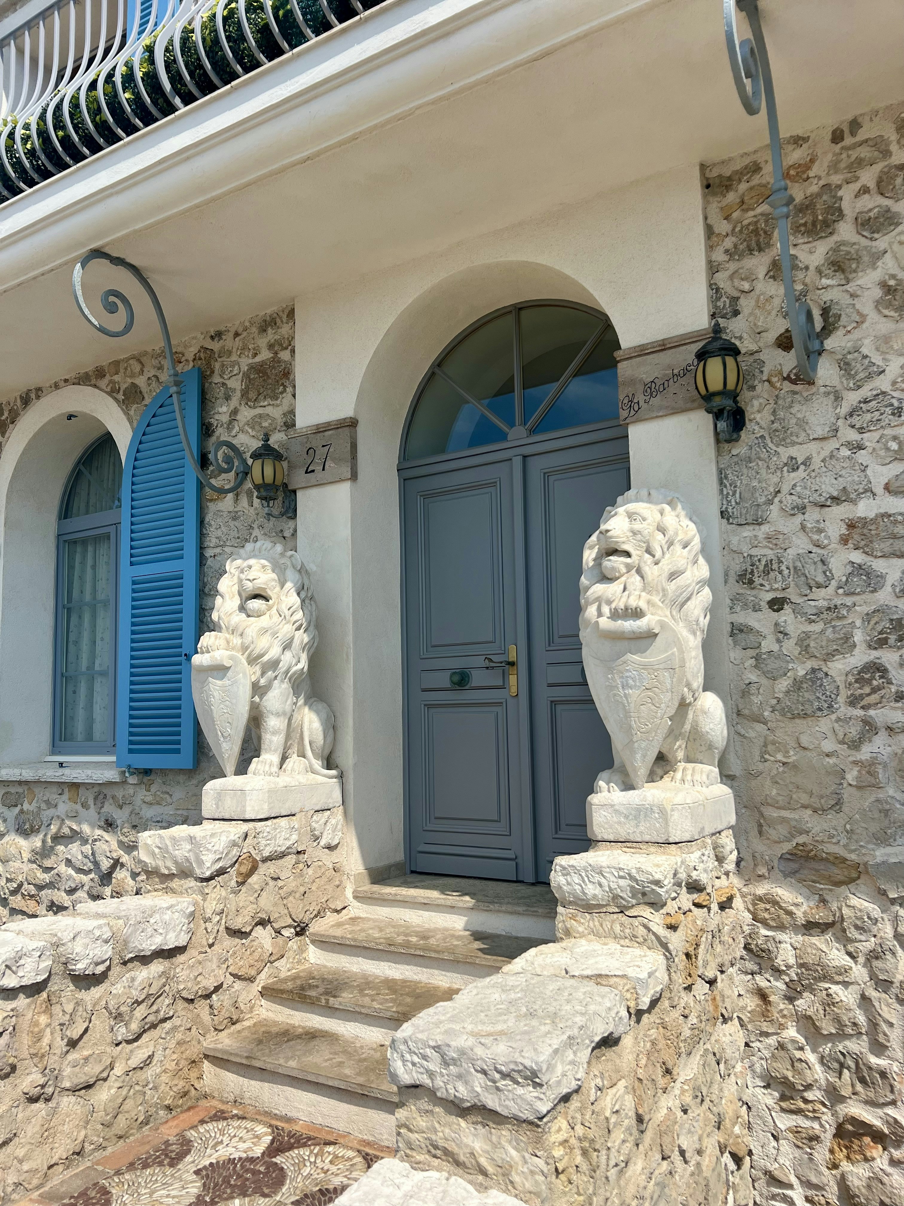 Stone lion statues flank a gray double door entrance.