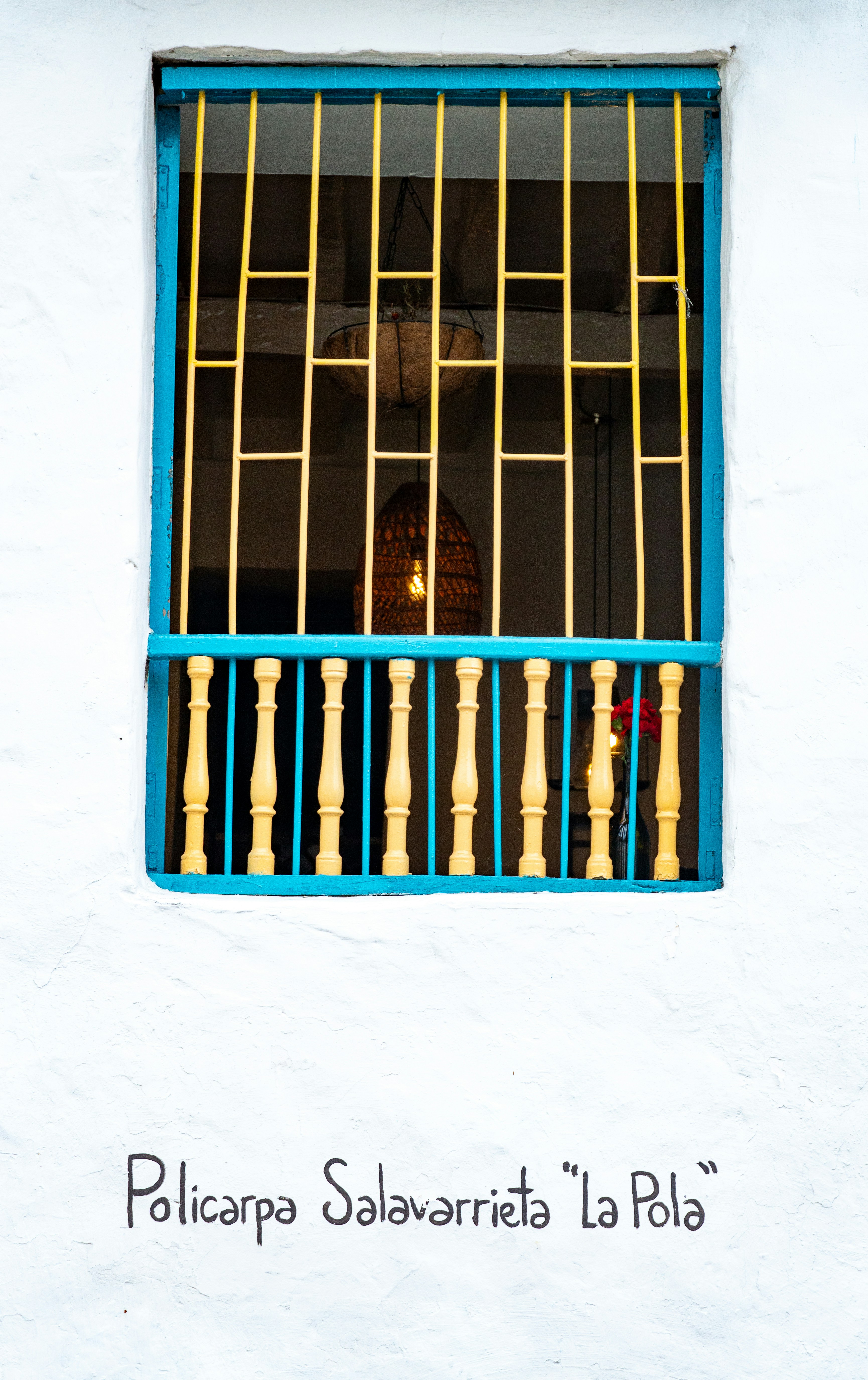 Window with blue and yellow bars on white wall.