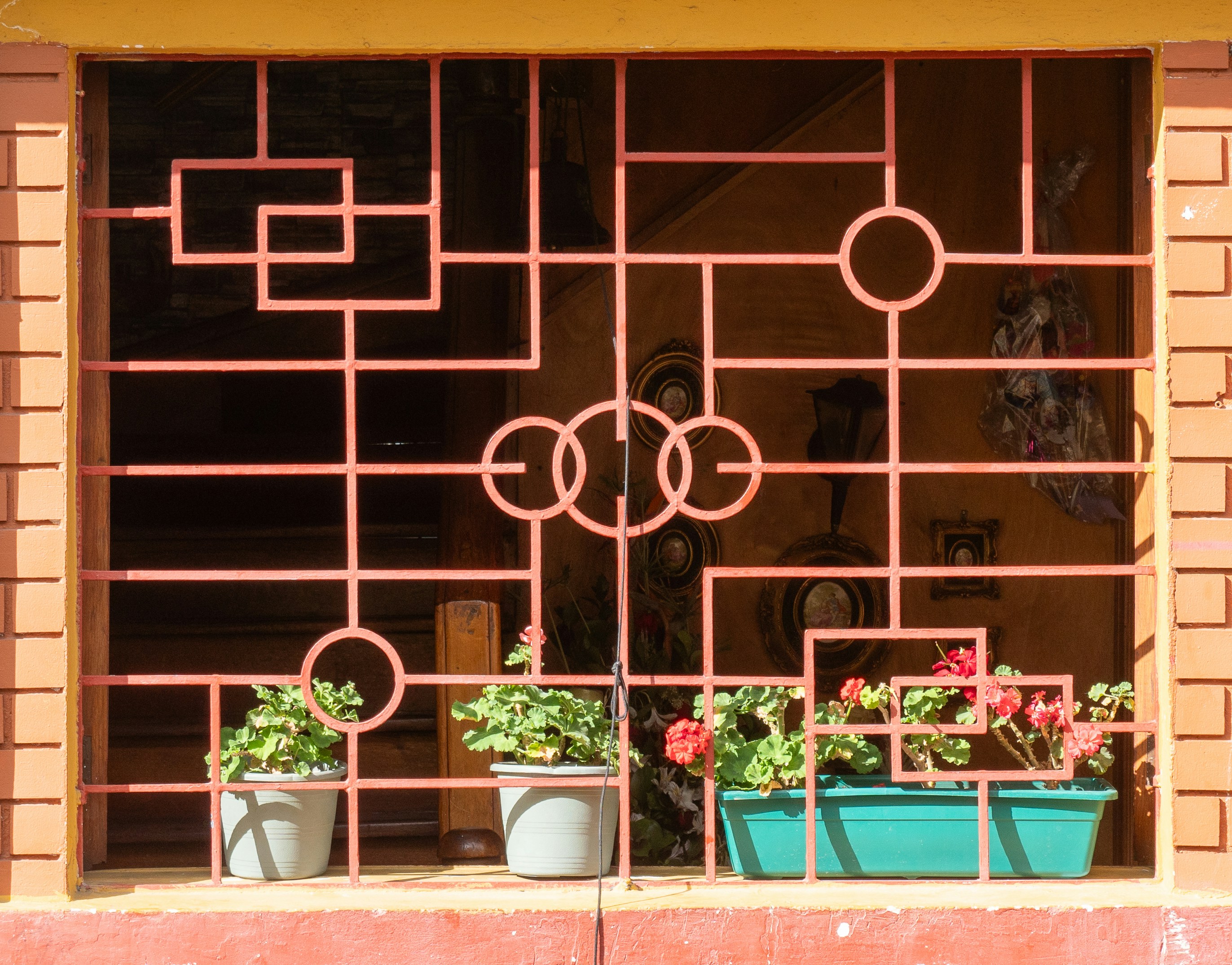 Decorative metal window grate with potted plants.