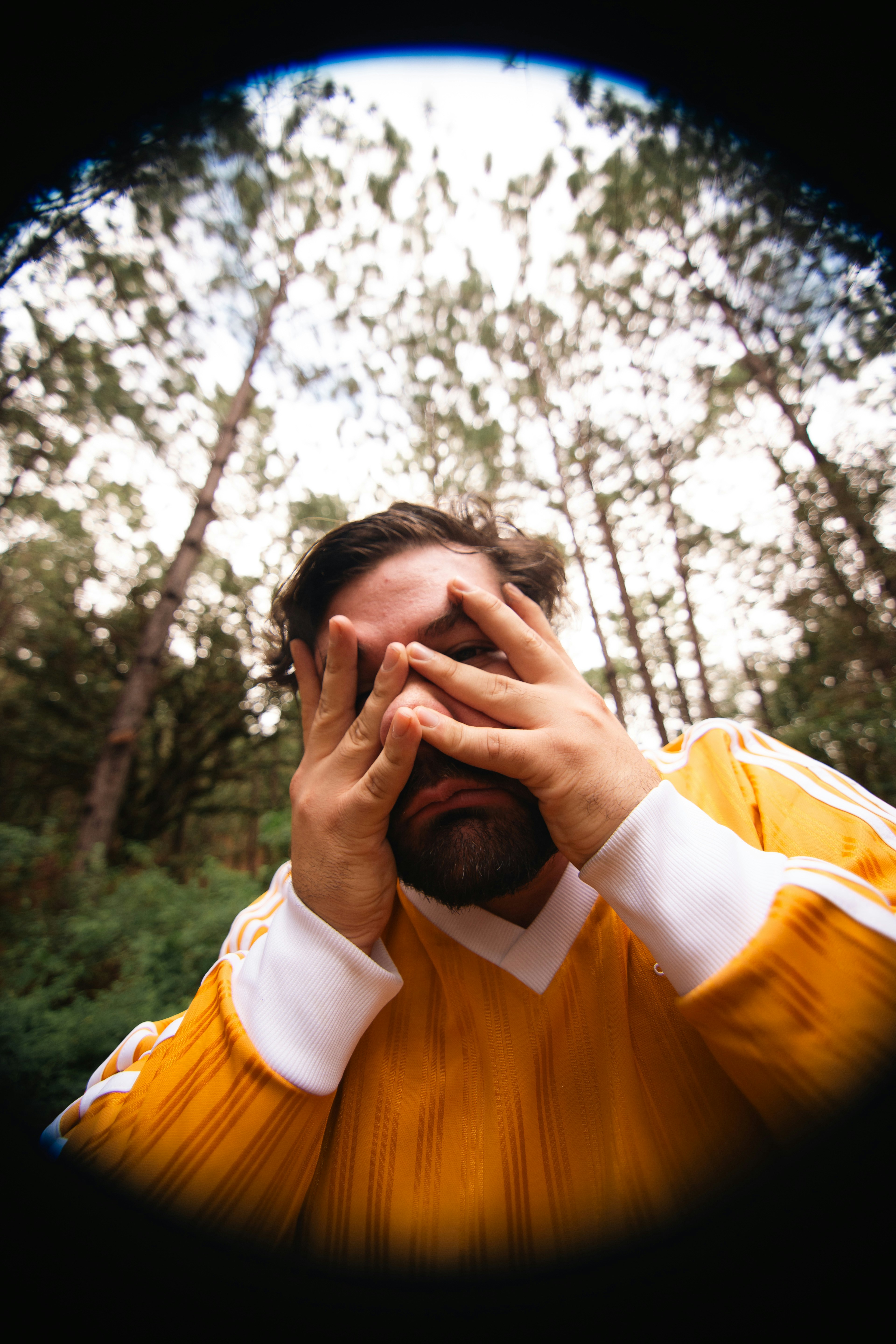 Man covers face with hands in forest