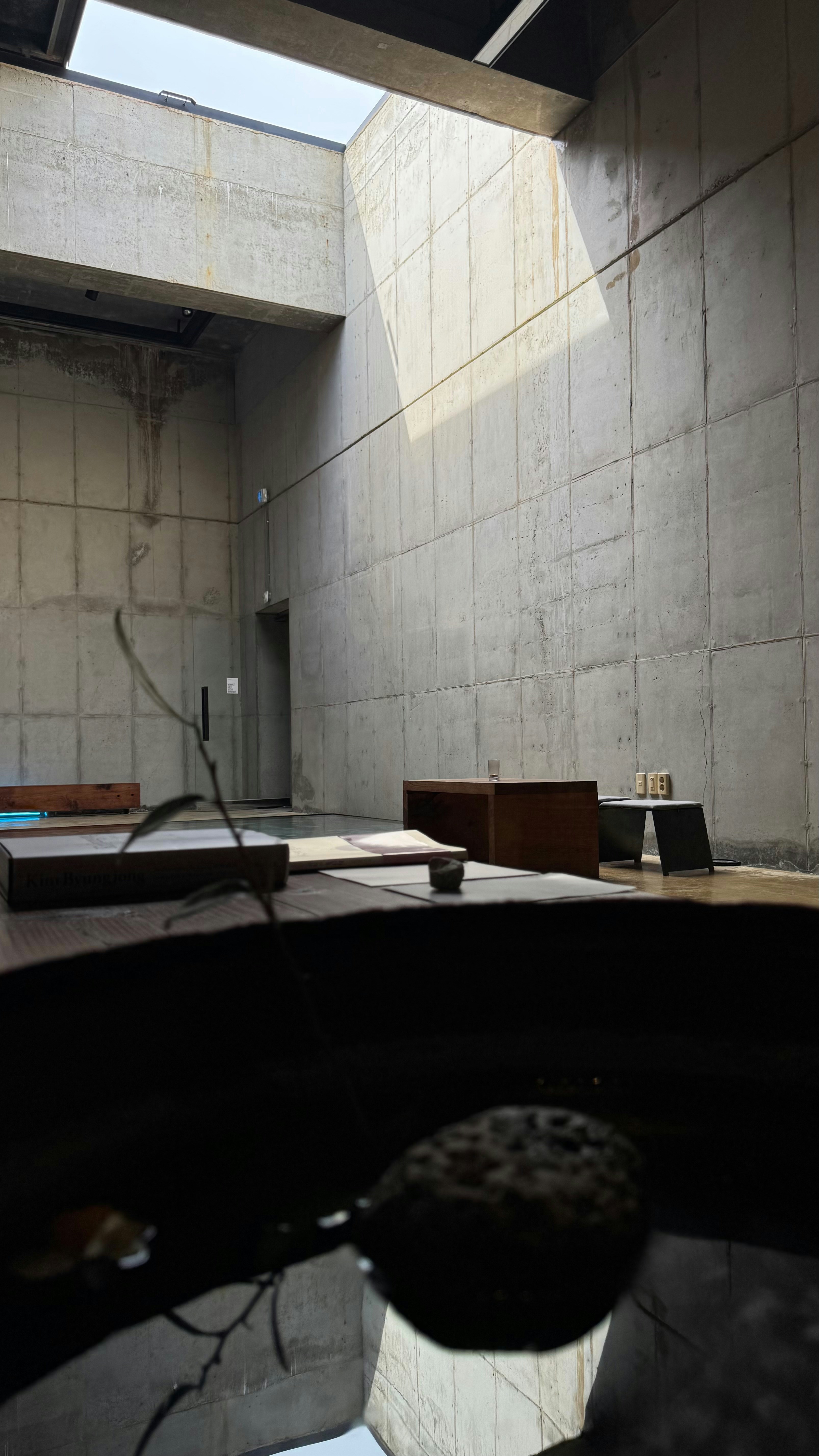 Sunlight streams into a concrete room with a water feature.