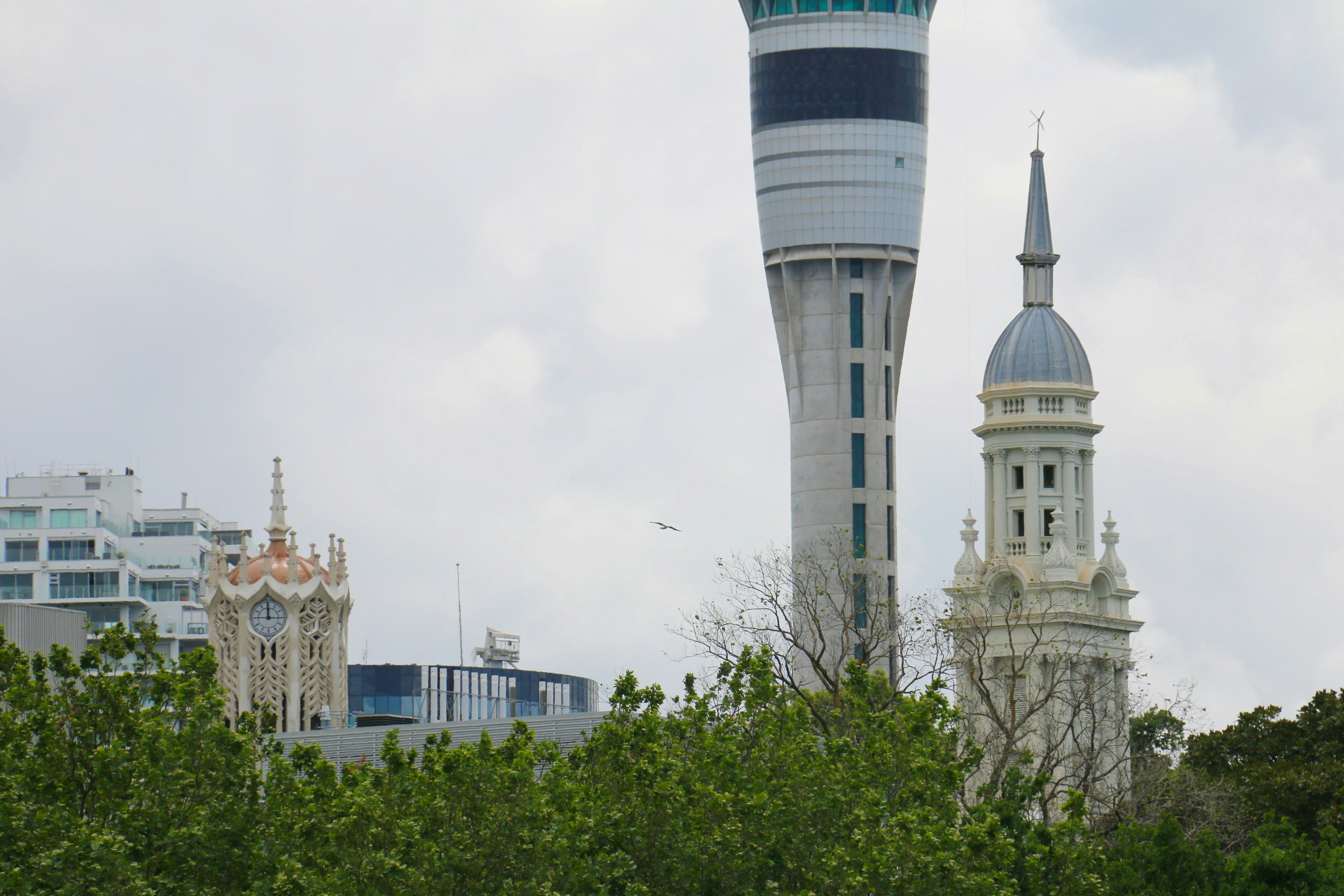 Old & New | Tall control tower beside ornate buildings and trees