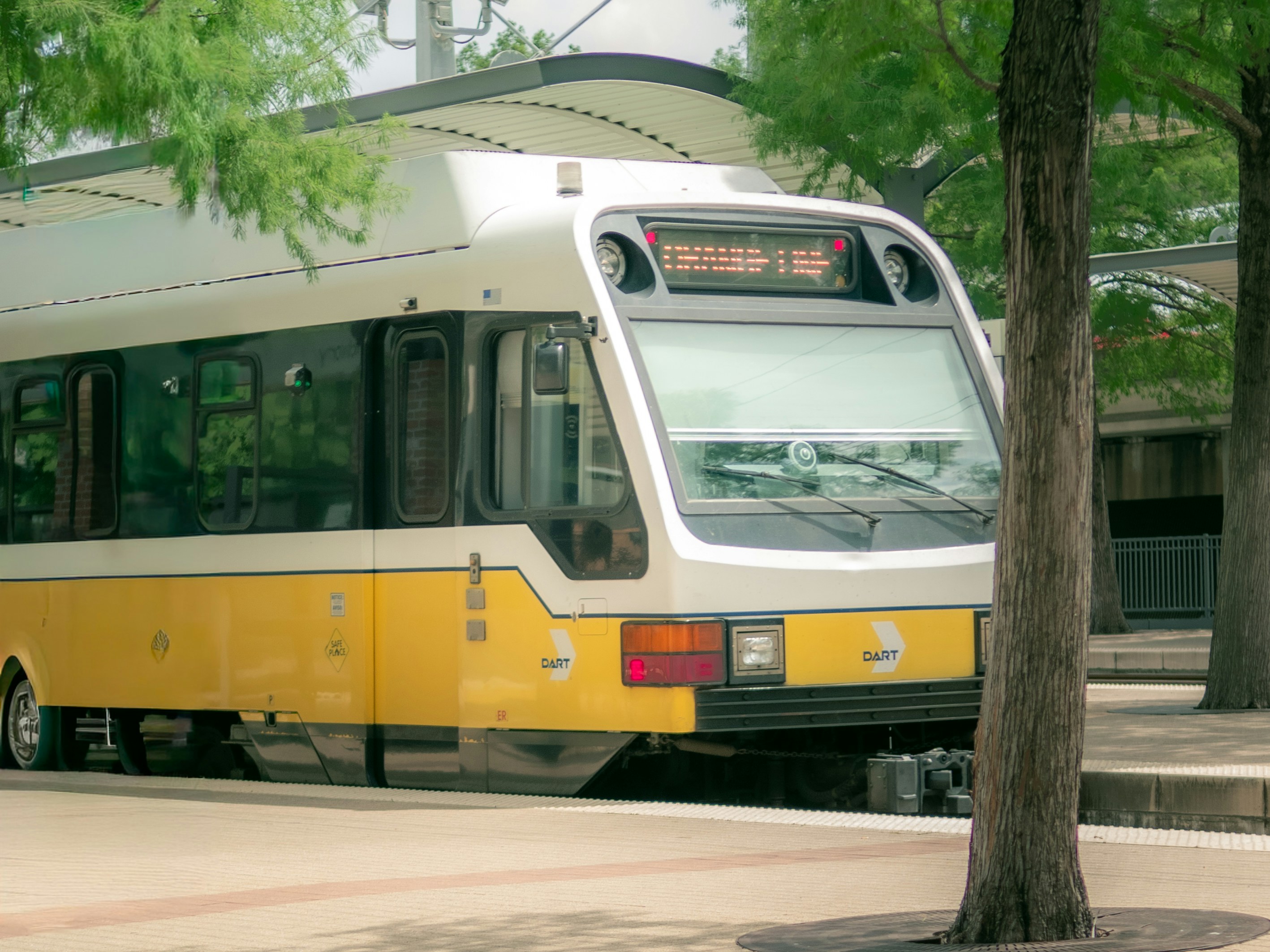 A modern train with yellow accents at a station.