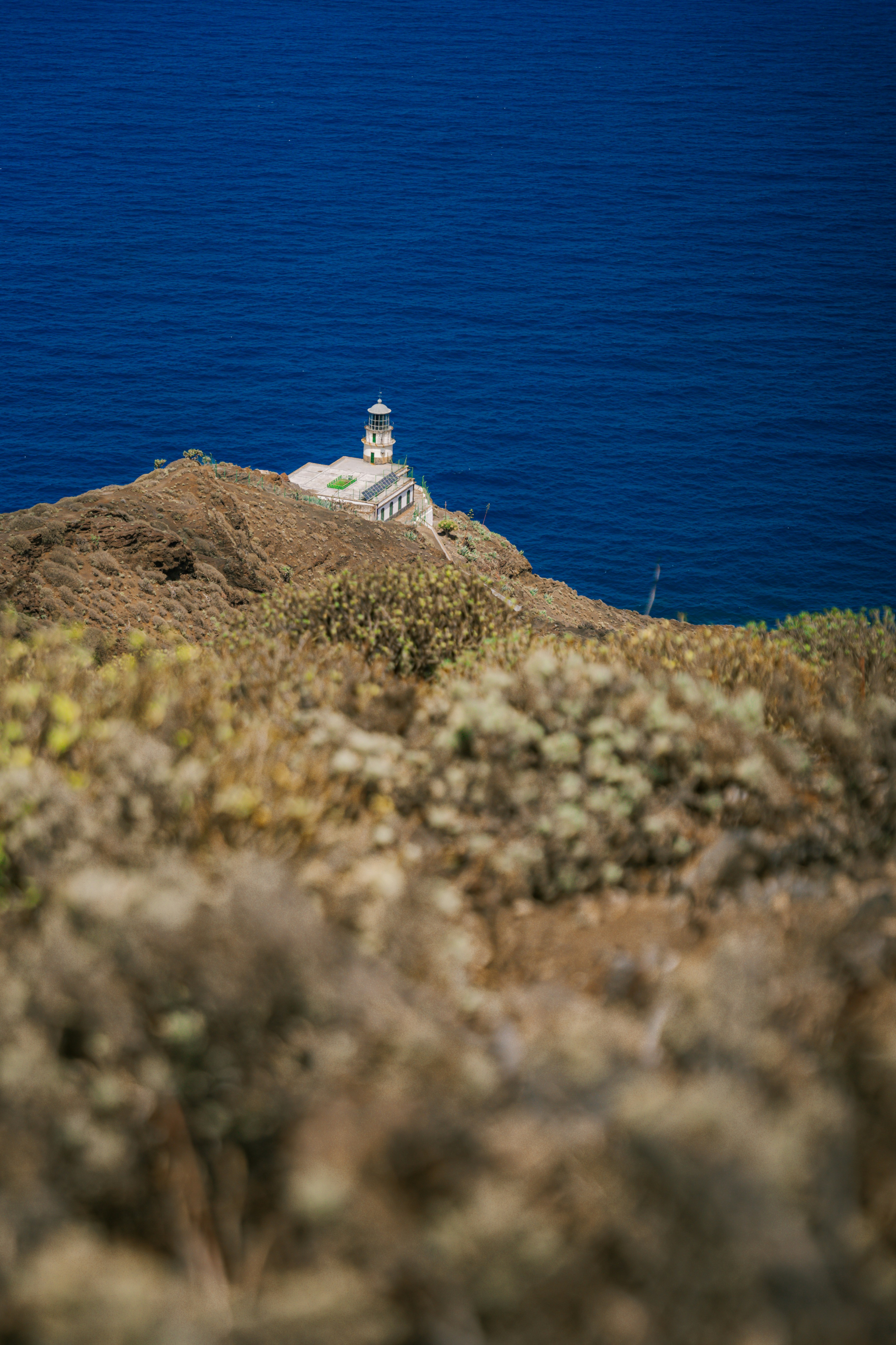 Lighthouse on a hill overlooking the deep blue sea.