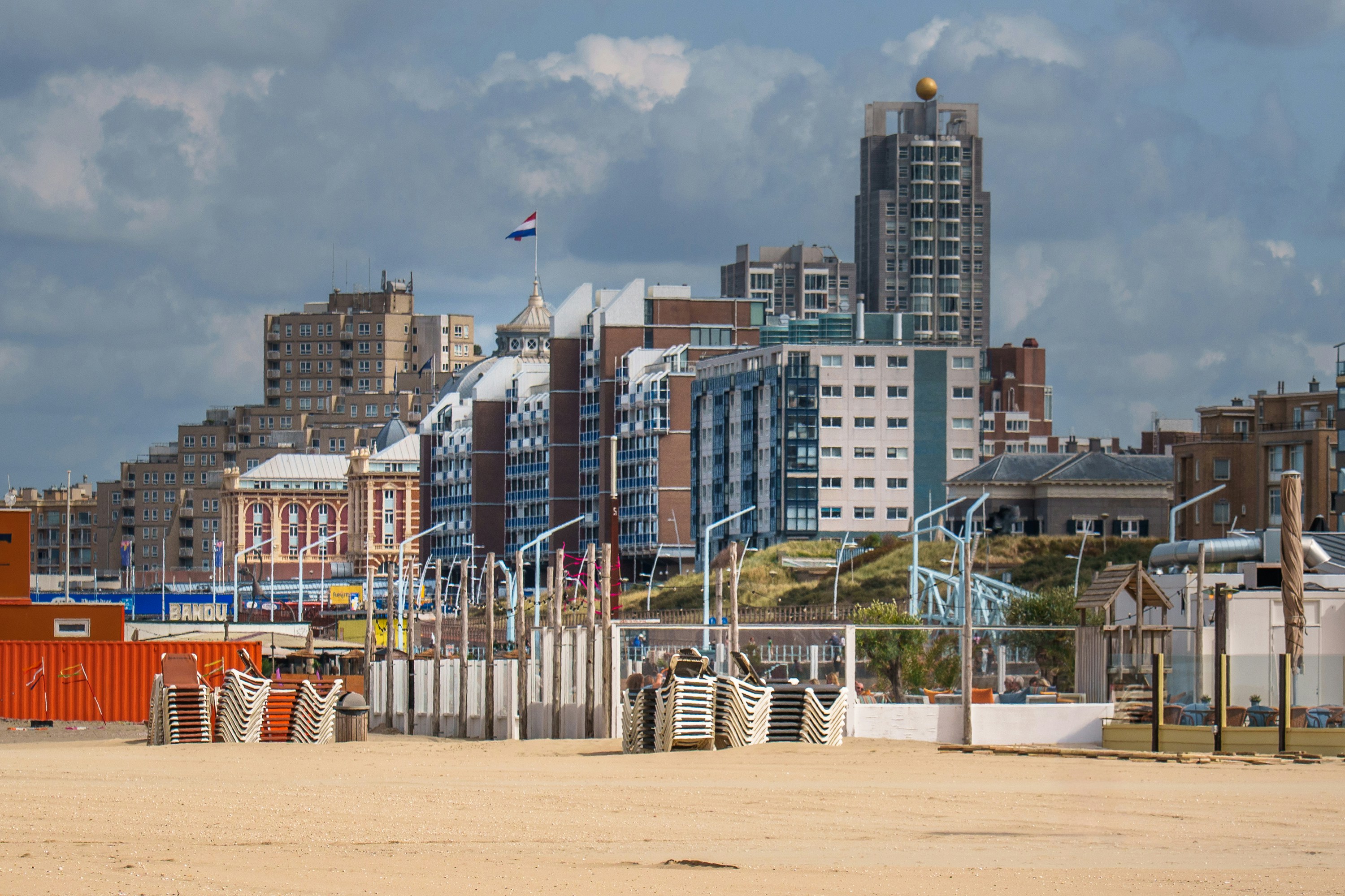 Scheveningen Beach Skyline Dutch Architecture Summer. Urban beachscape with modern and historical buildings in The Hague Scheveningen district | Buildings line a sandy beach under cloudy skies.