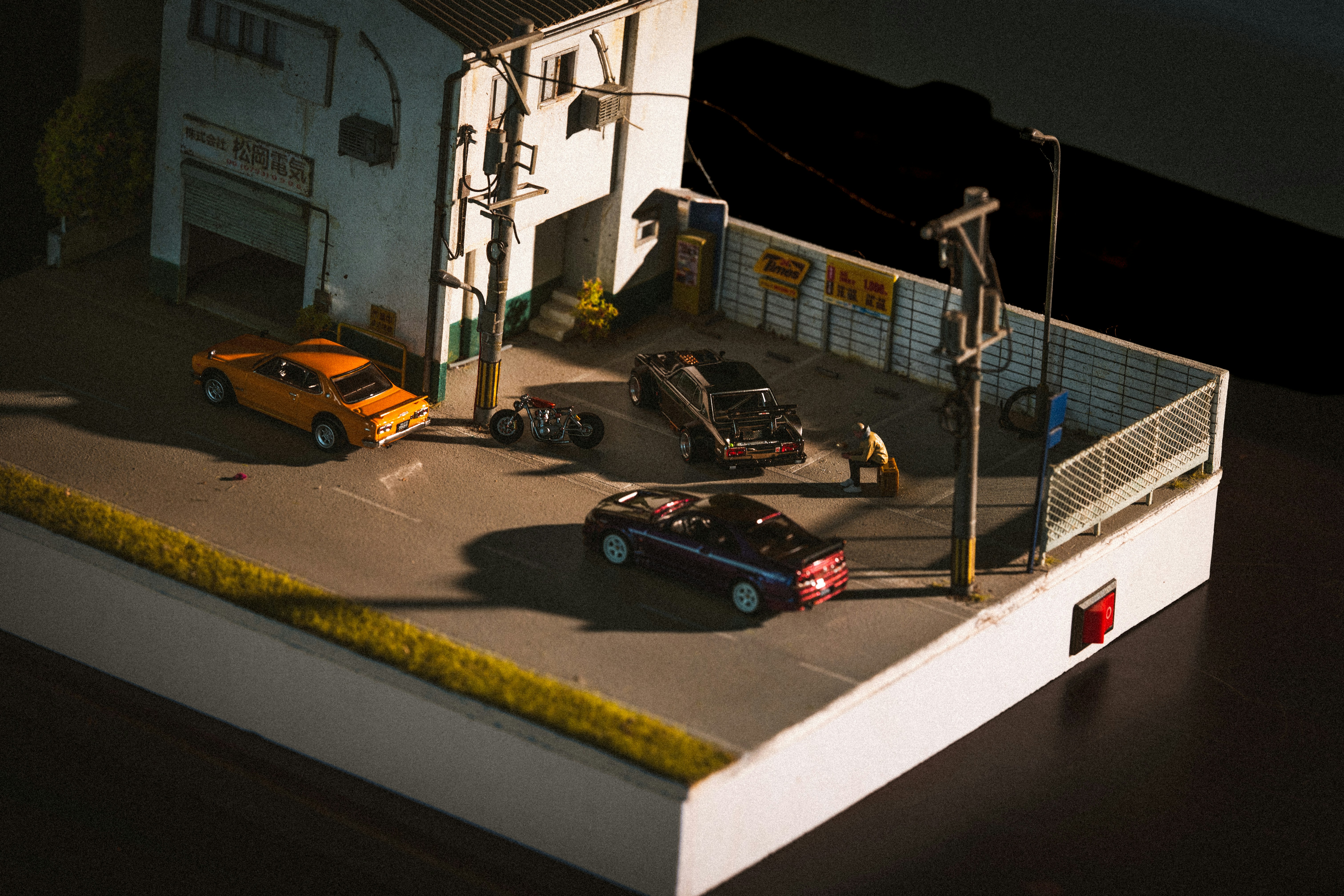 Diorama of a garage scene with cars and figures.