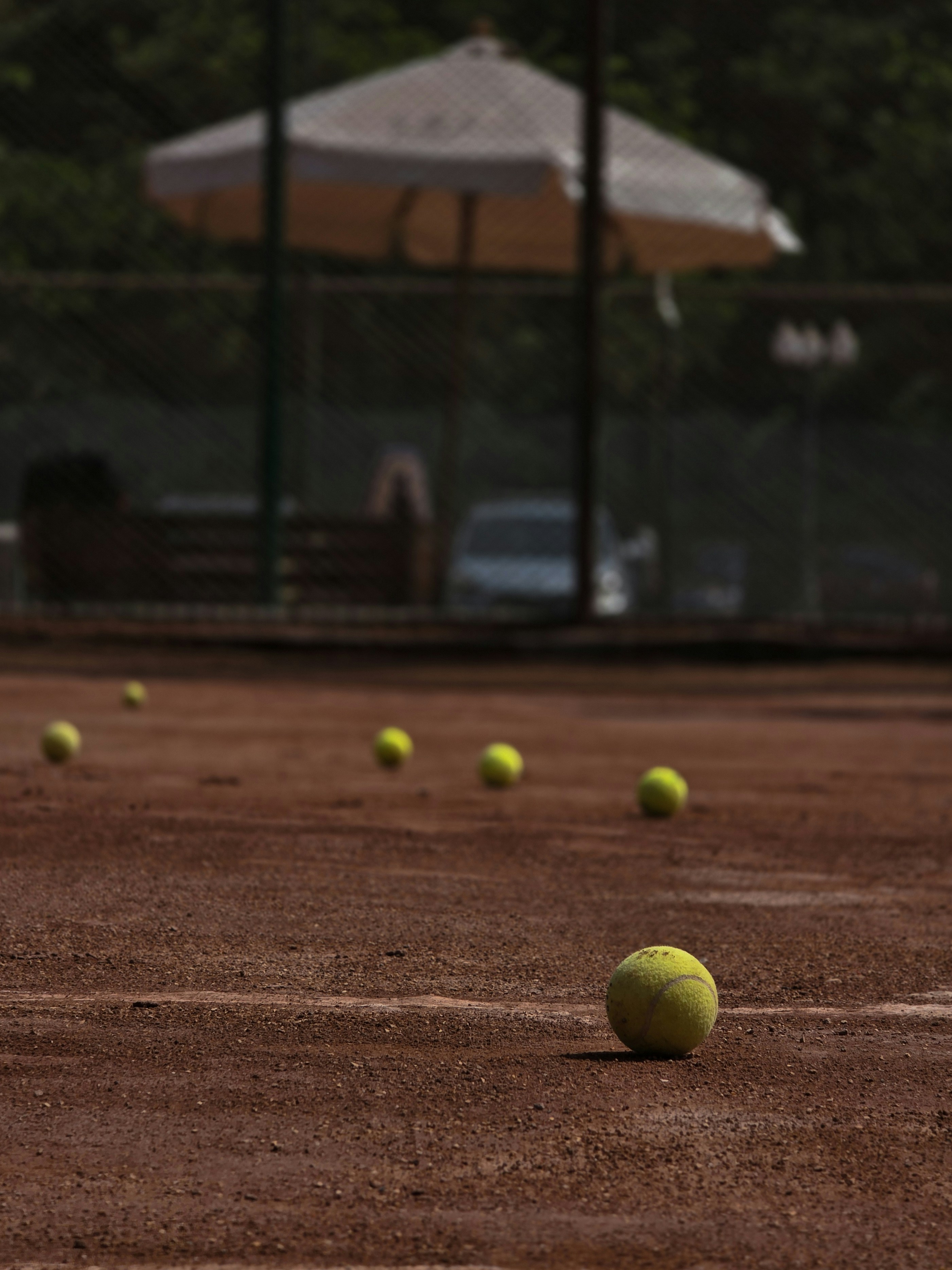 Tennis balls lined up on a clay court
