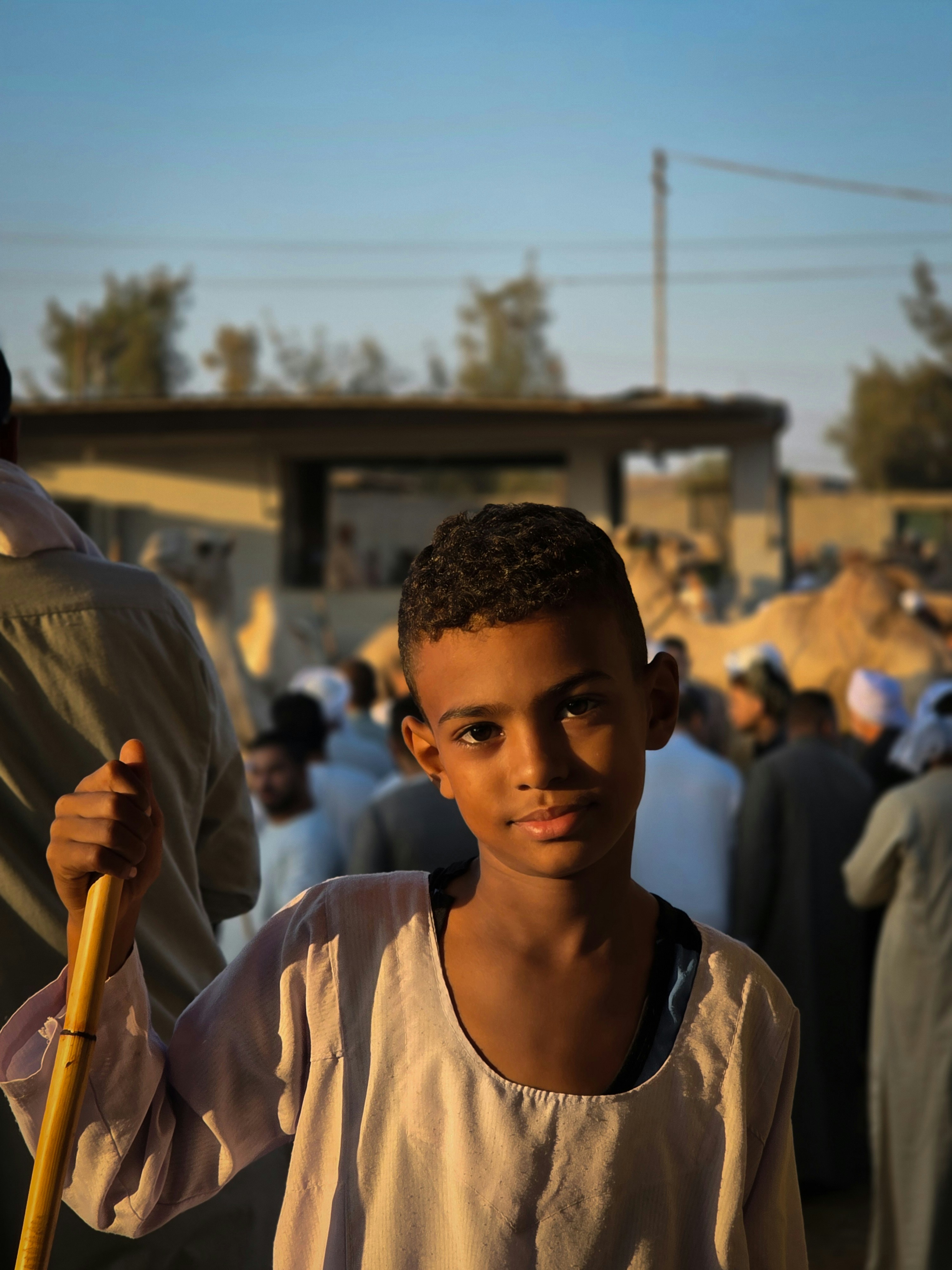 Young boy holding a stick in a crowd