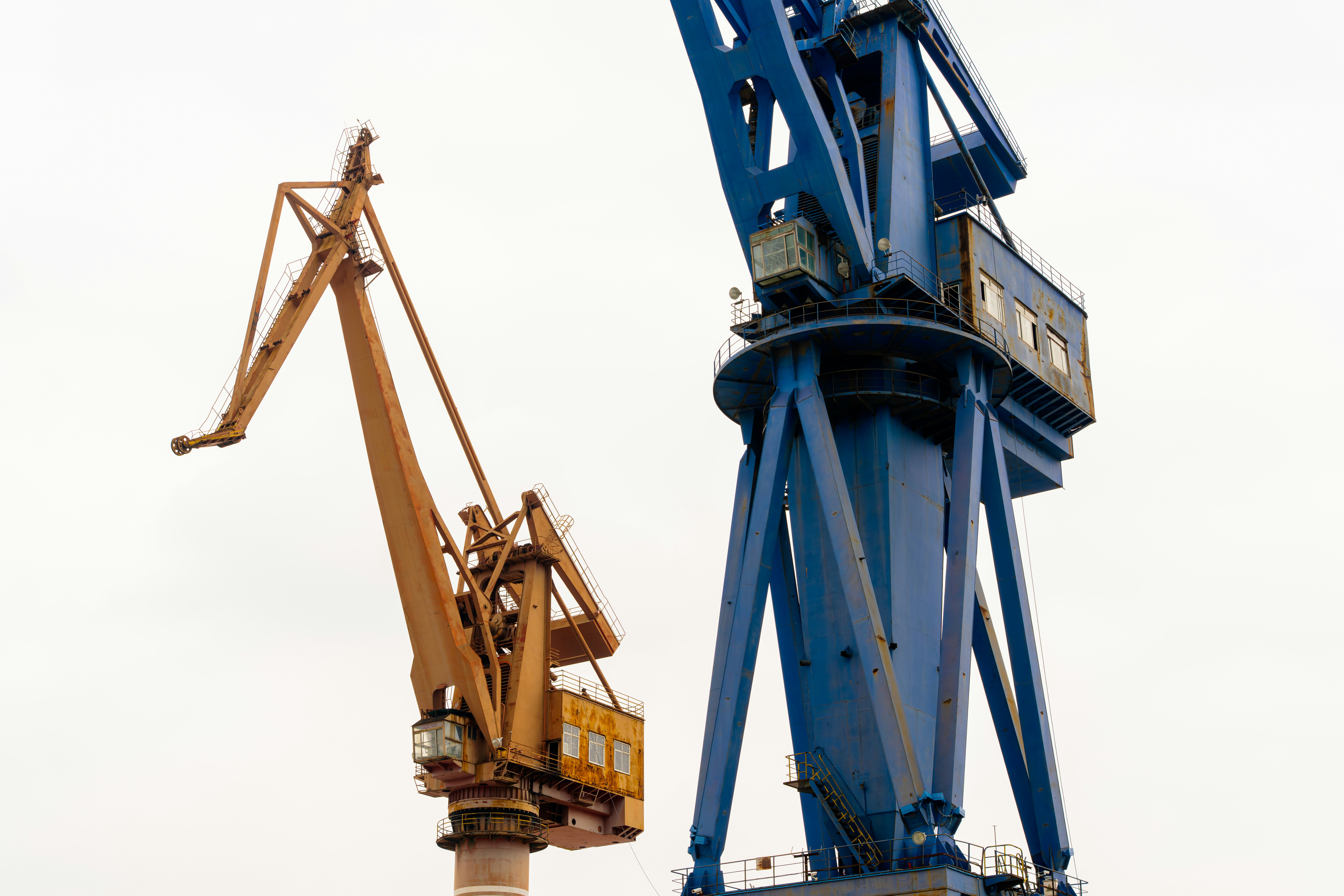 Two industrial cranes against a cloudy sky