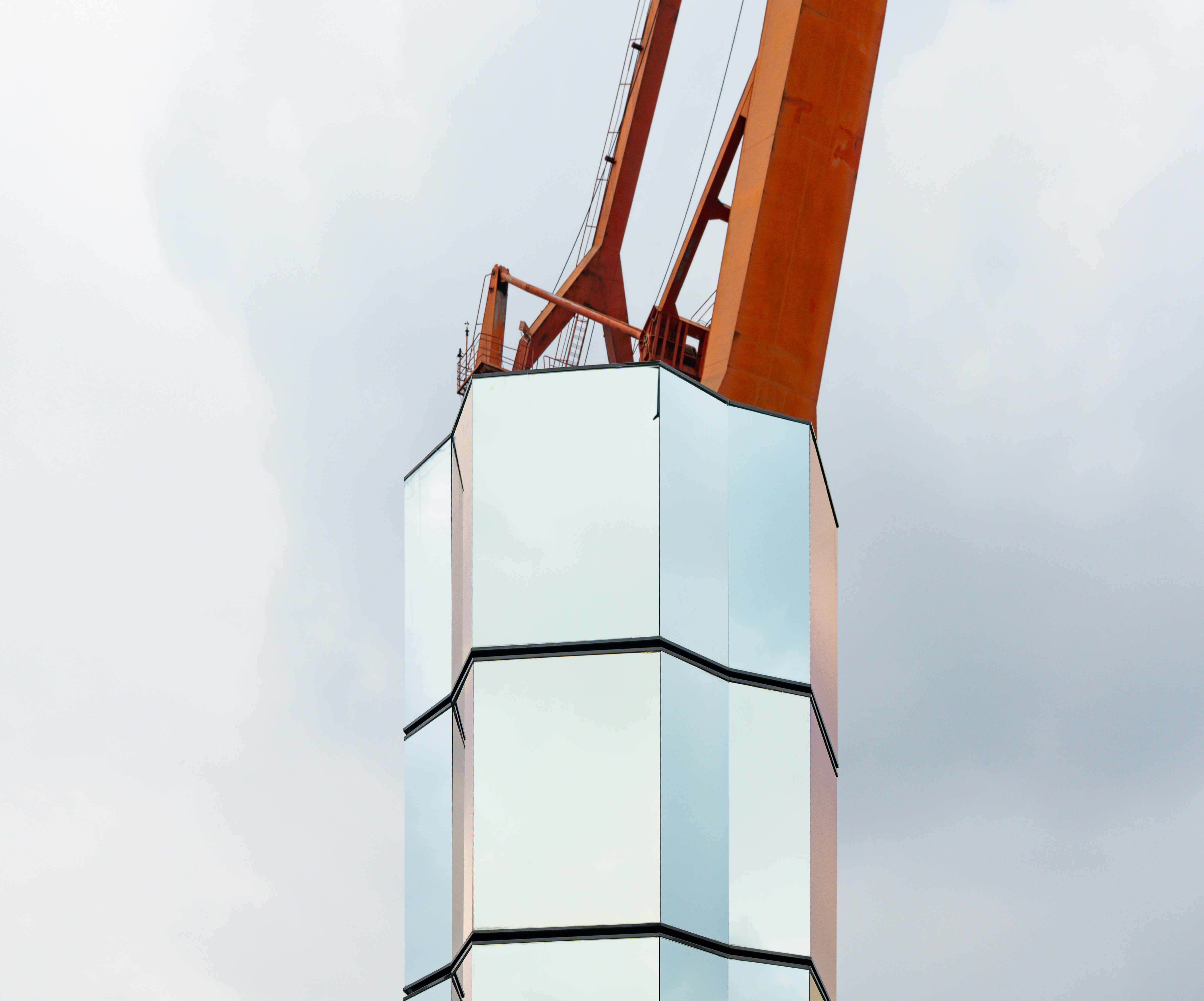 Crane-Crowned Glass Prism Reaching into a Cloudy Sky