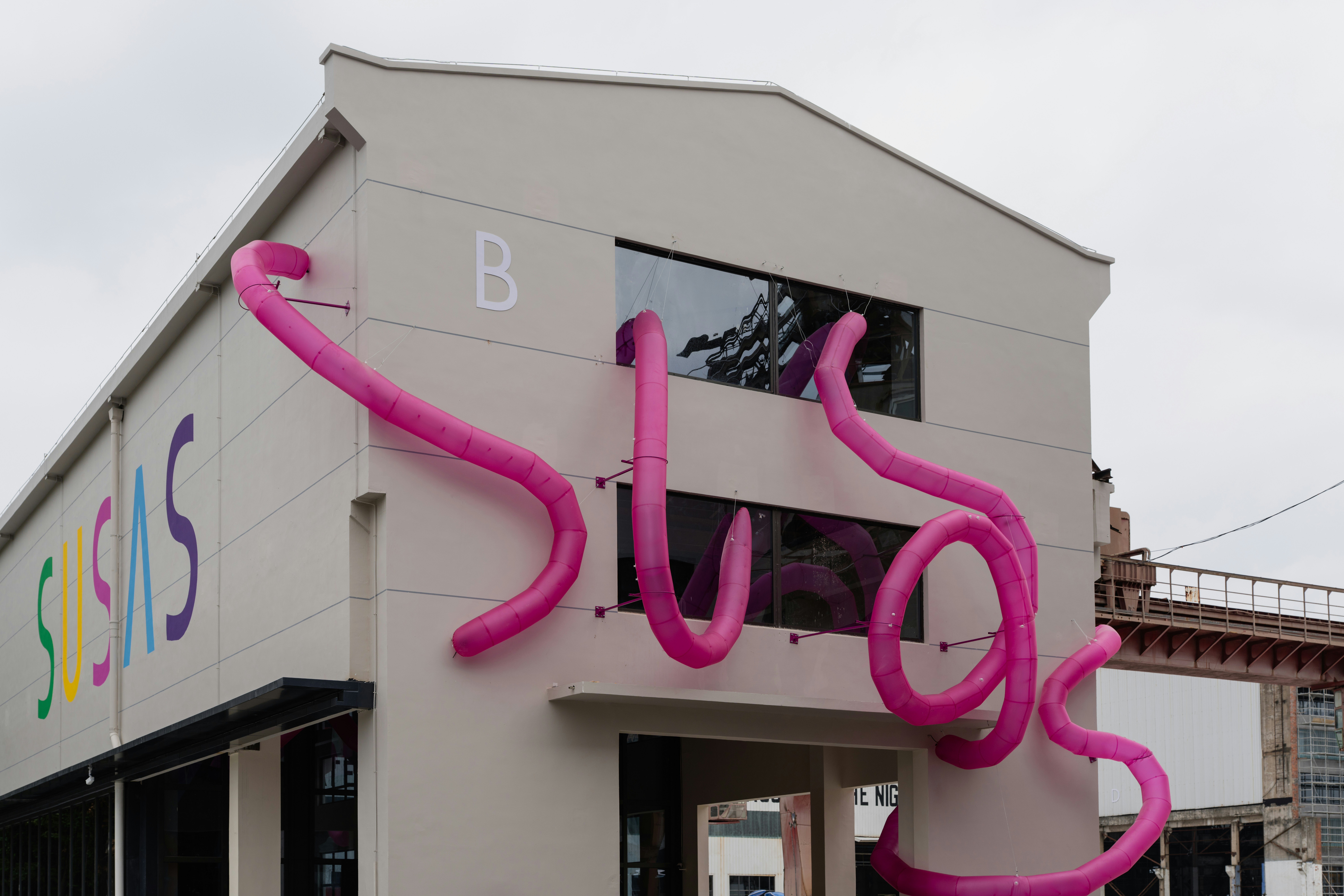 Inflatable pink tubes on a building with colorful text