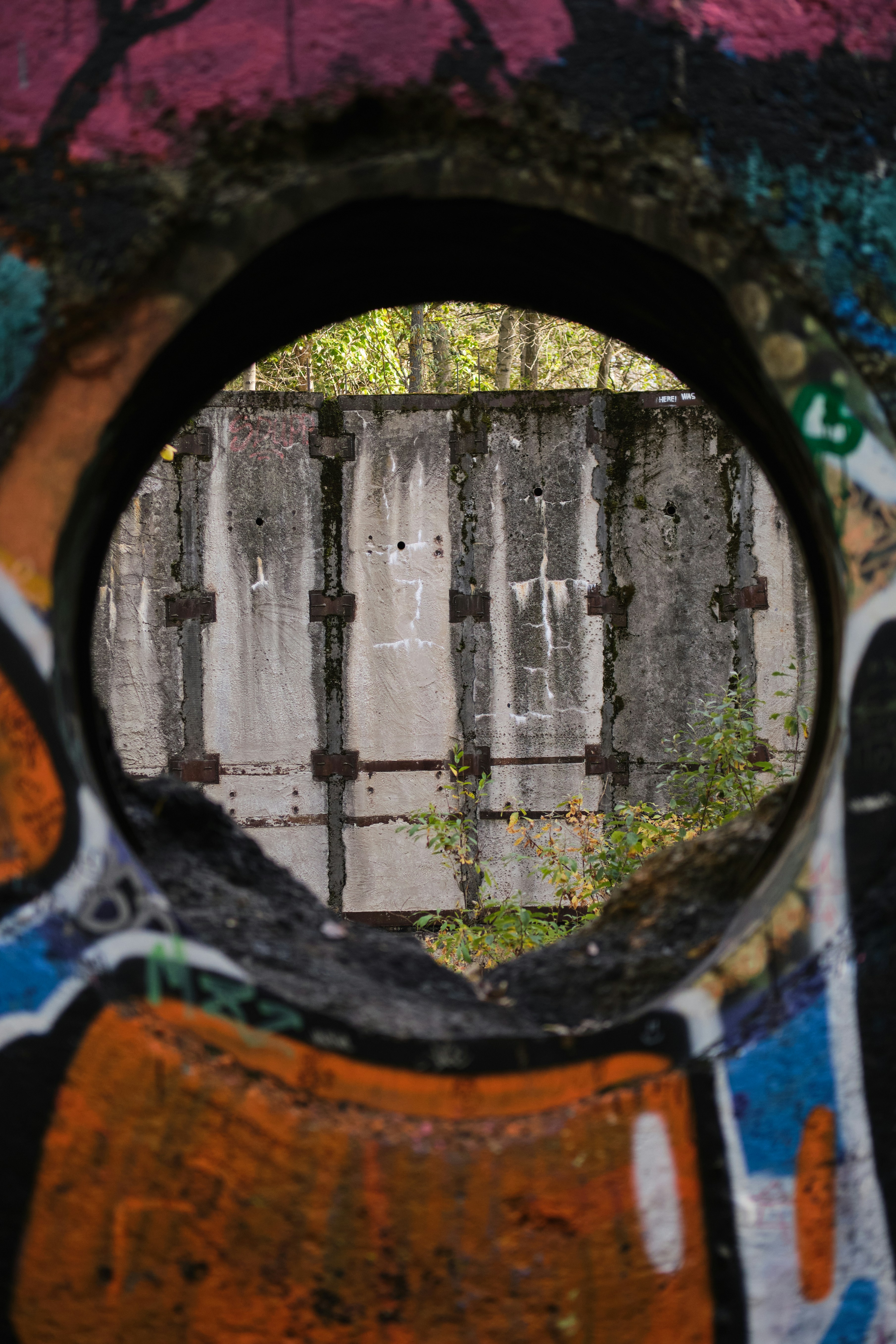 Graffiti surrounds concrete wall through circular opening