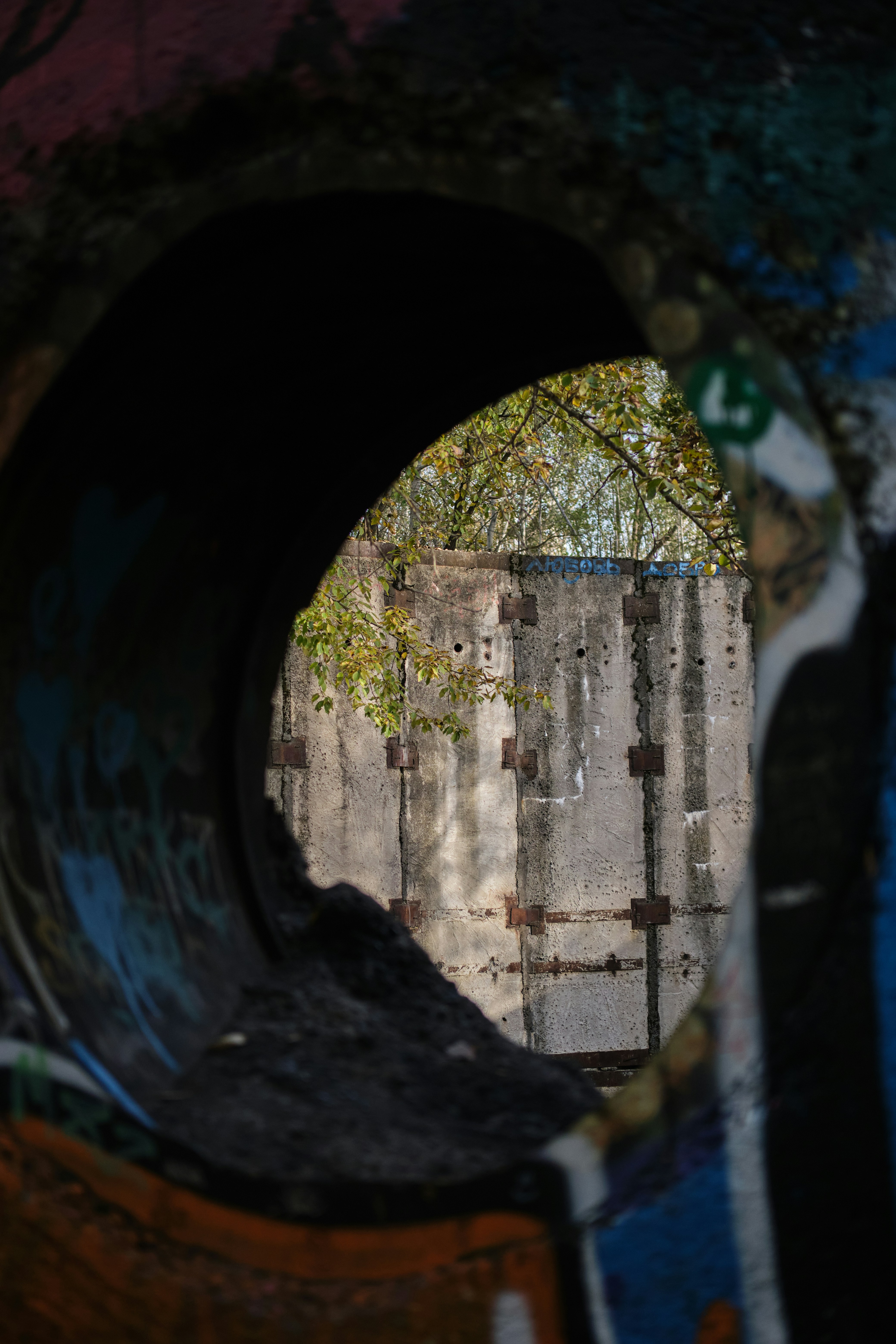 View through a dark opening to a concrete wall.