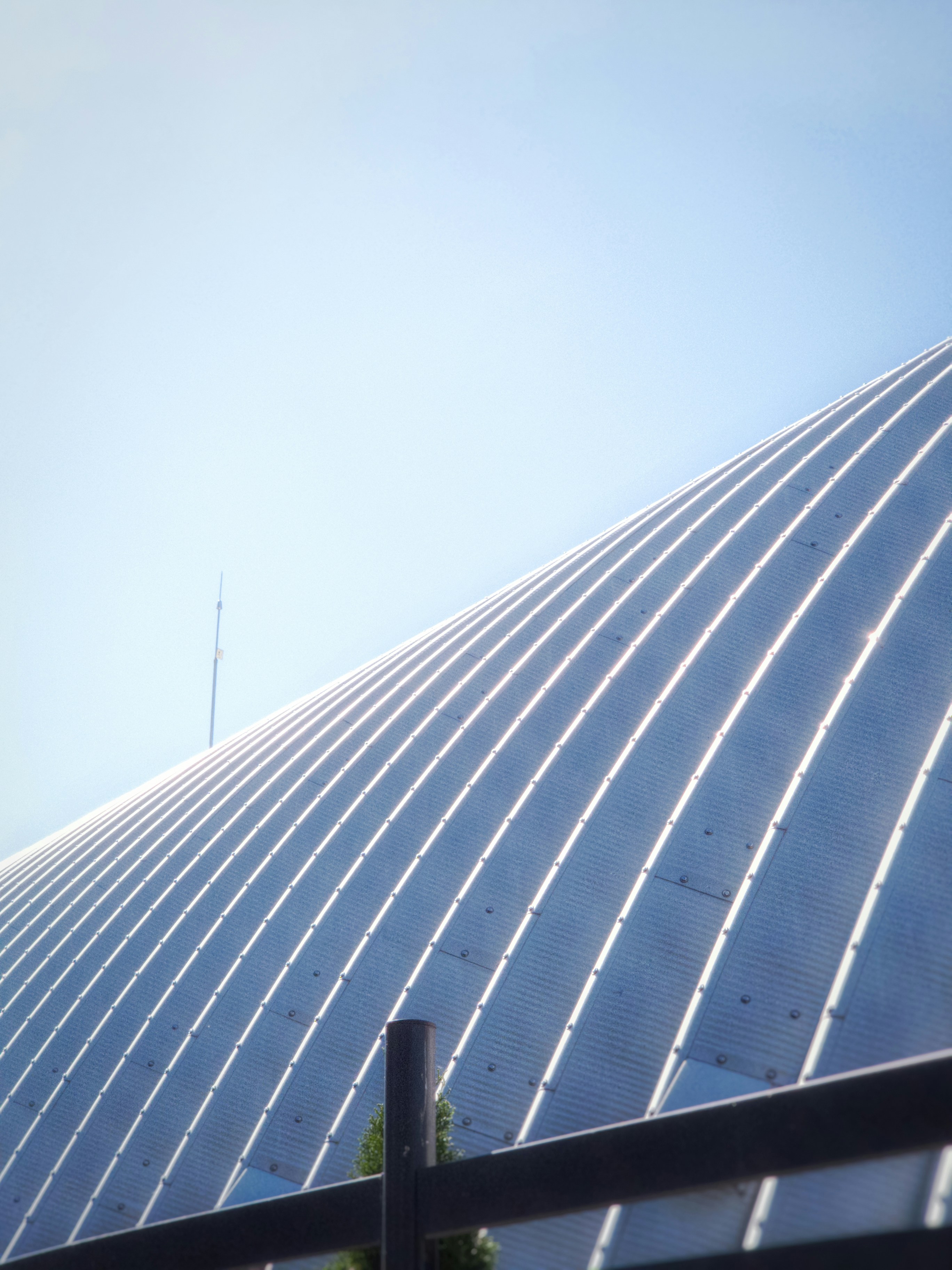 Curved metallic roof with clear blue sky