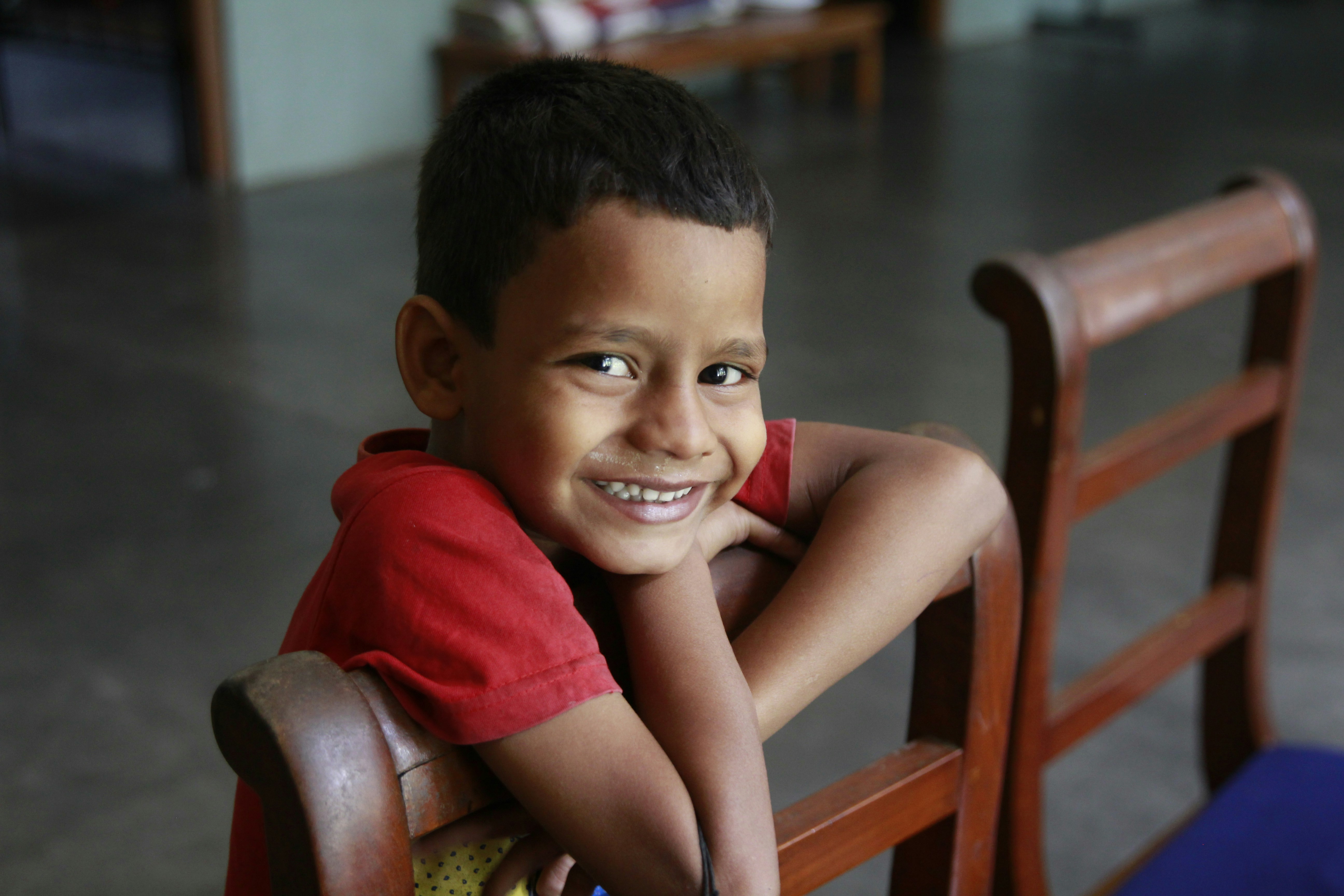 A child in India, Calcutta | A young boy in a red shirt smiles warmly.